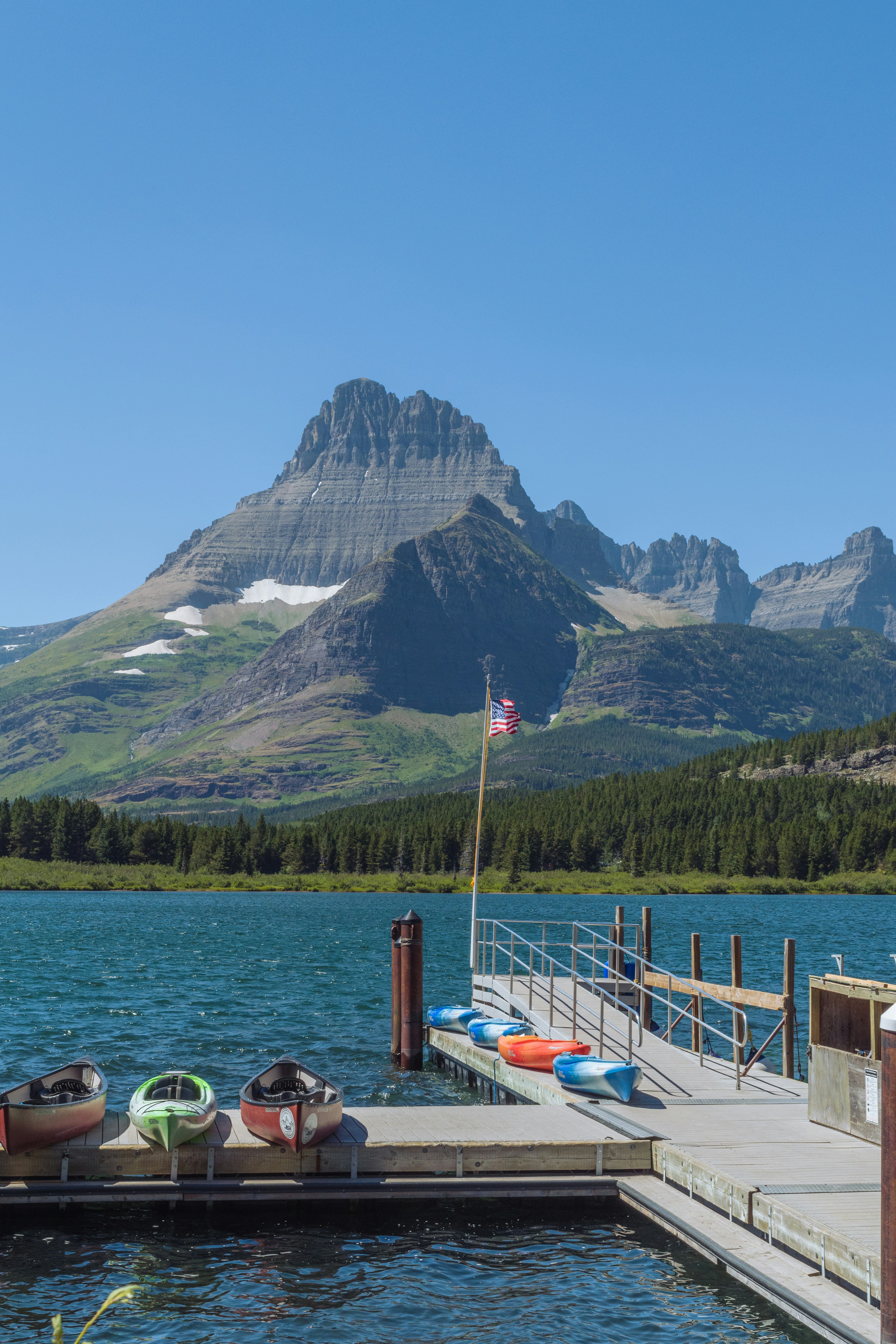 Foto Un muelle con kayaks en un lago con montañas al fondo – Imagen ...