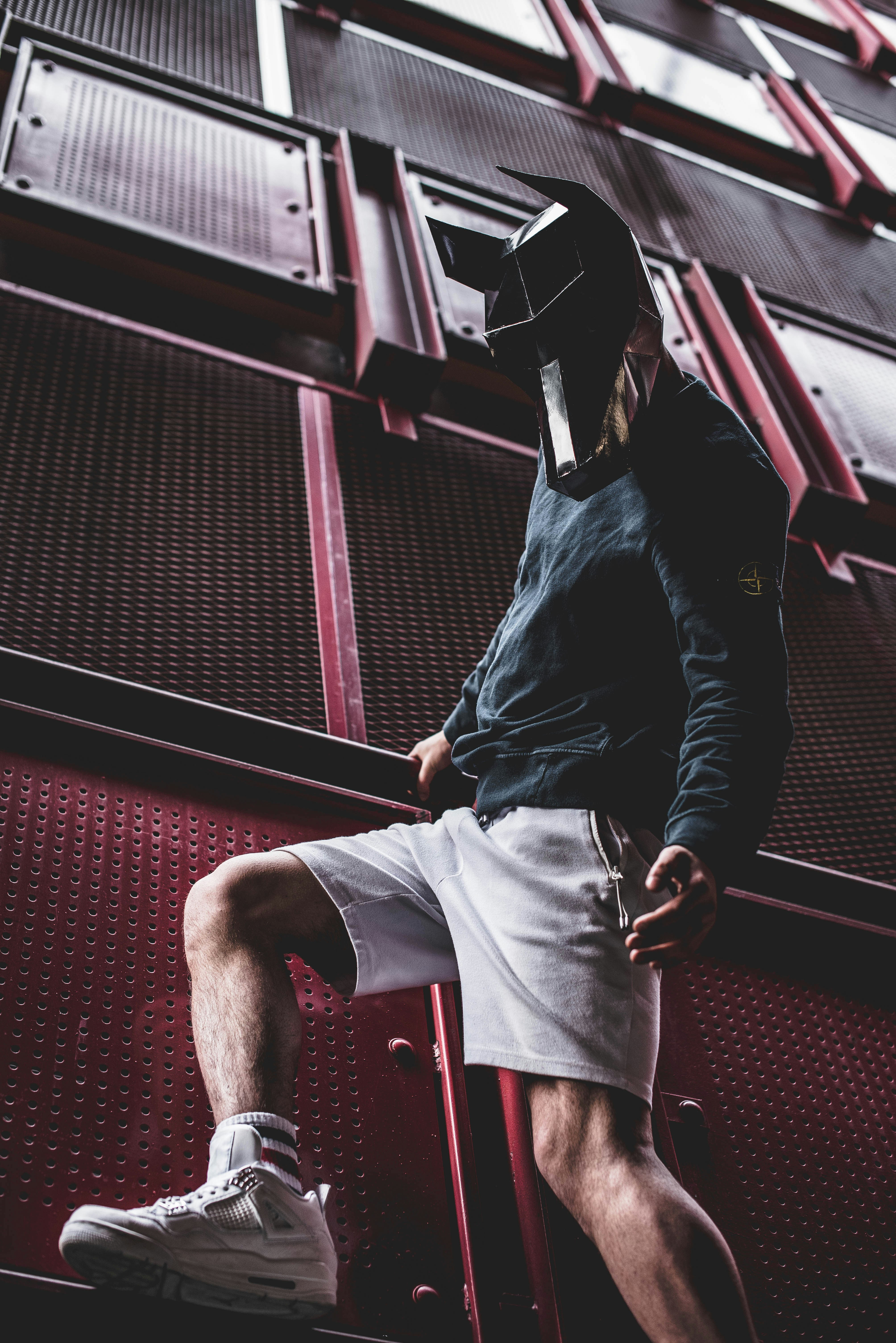 Armored Mask, Grounded Steps: A Shadowed Figure Strides Under Industrial Rust