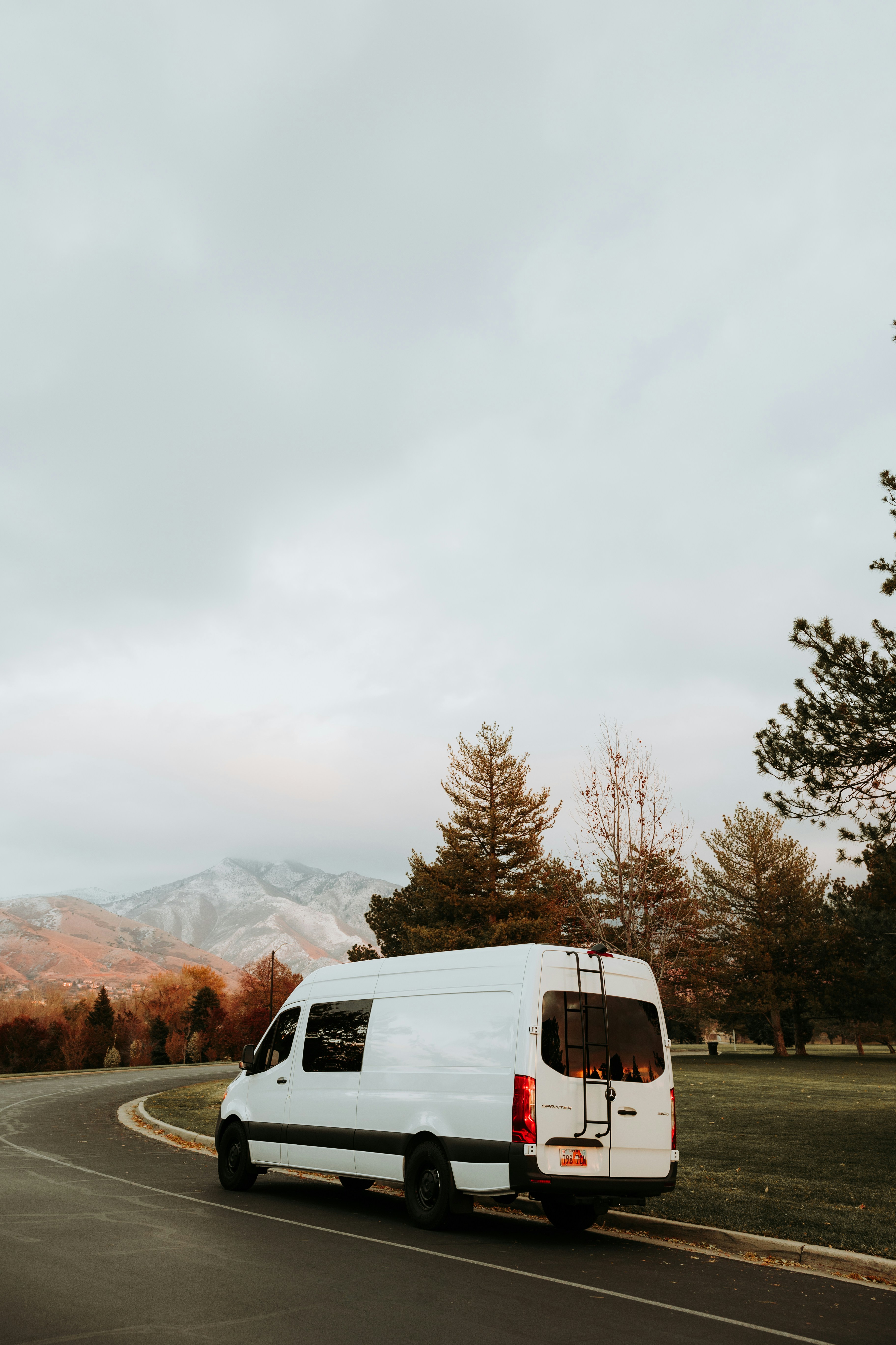 A white van driving down a curvy road photo – Free Mountains Image on ...