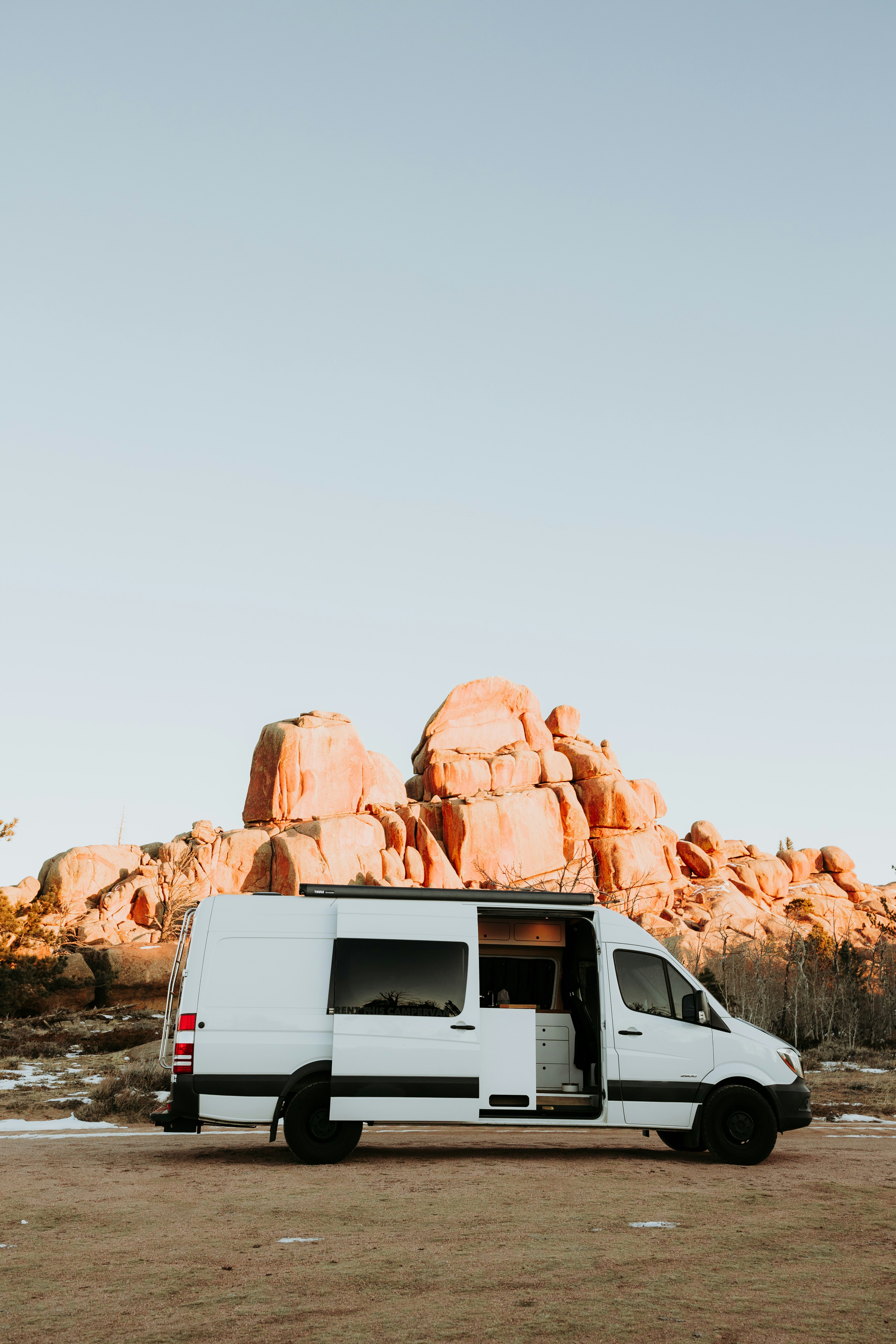 A white van parked in front of a large rock formation photo – Free ...