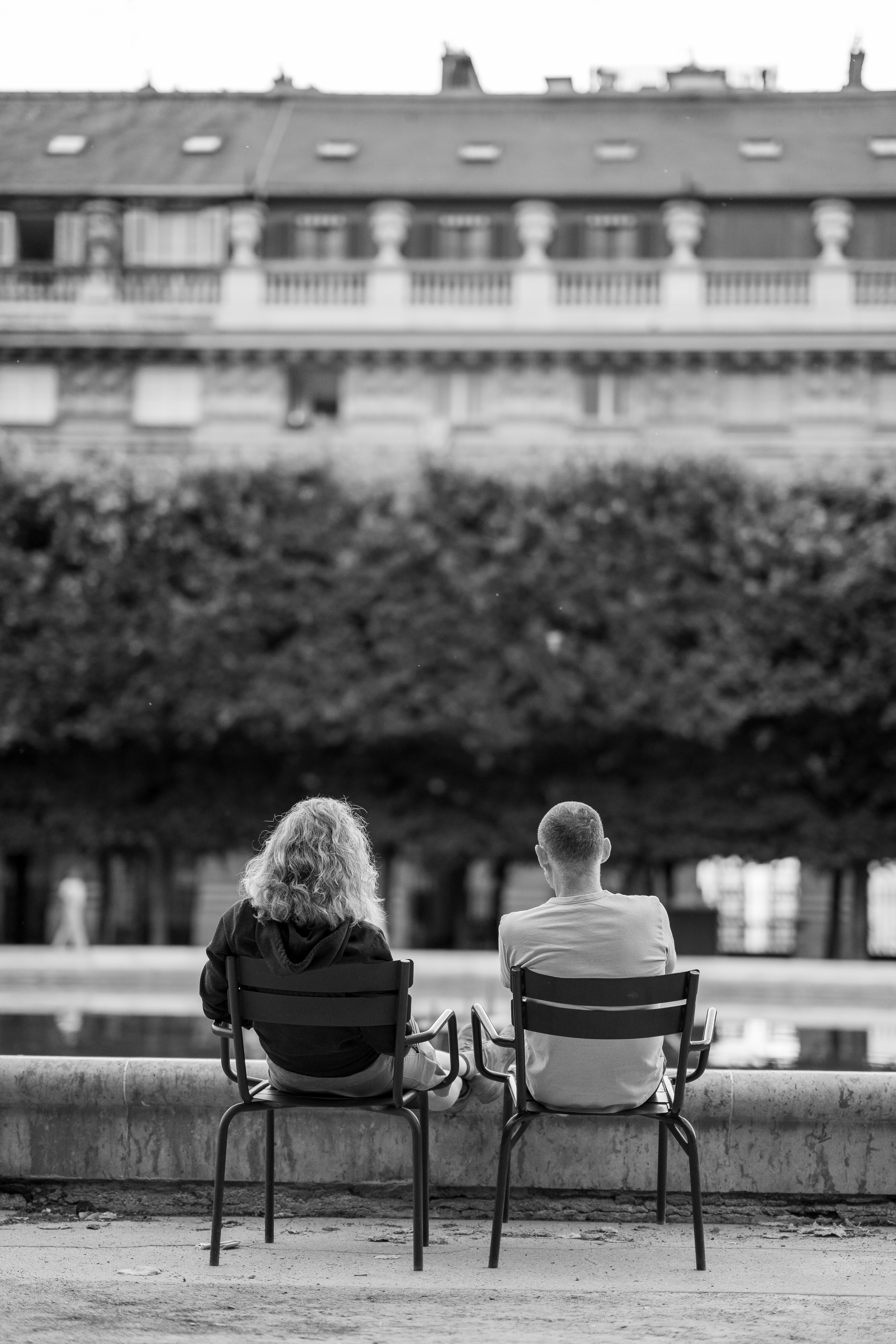 Back to the City: Two Figures on a Riverside Bench Framed by a Parisian Façade