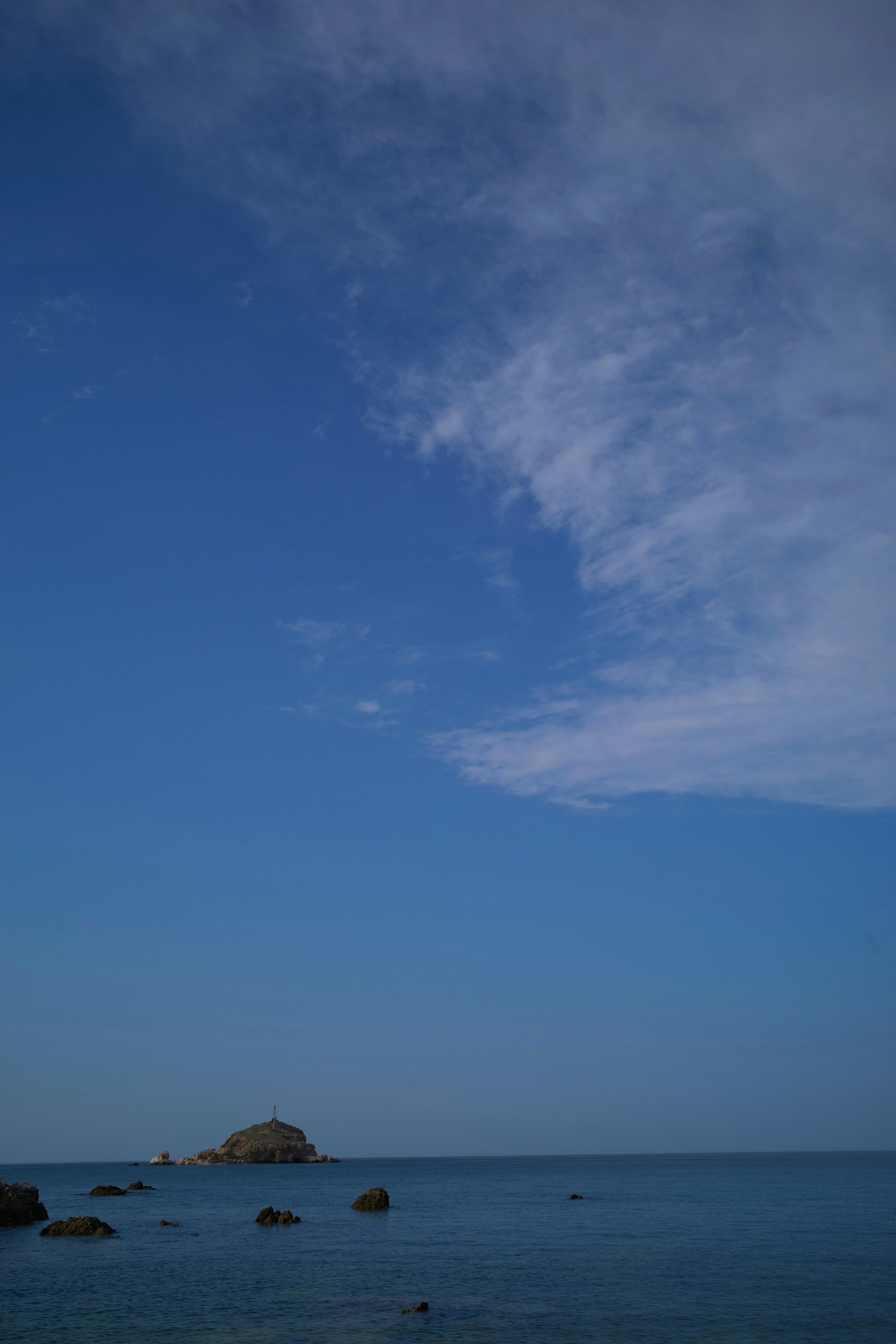 Distant Beacon on a Quiet Isle Under Expansive Blue