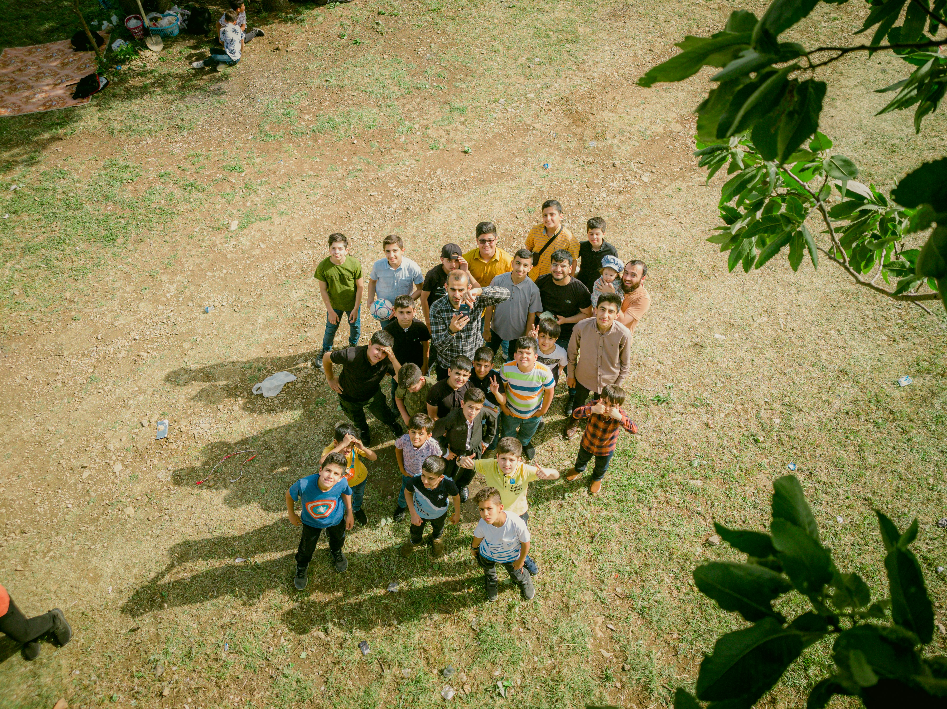 A group of people standing on top of a grass covered field photo – Free ...