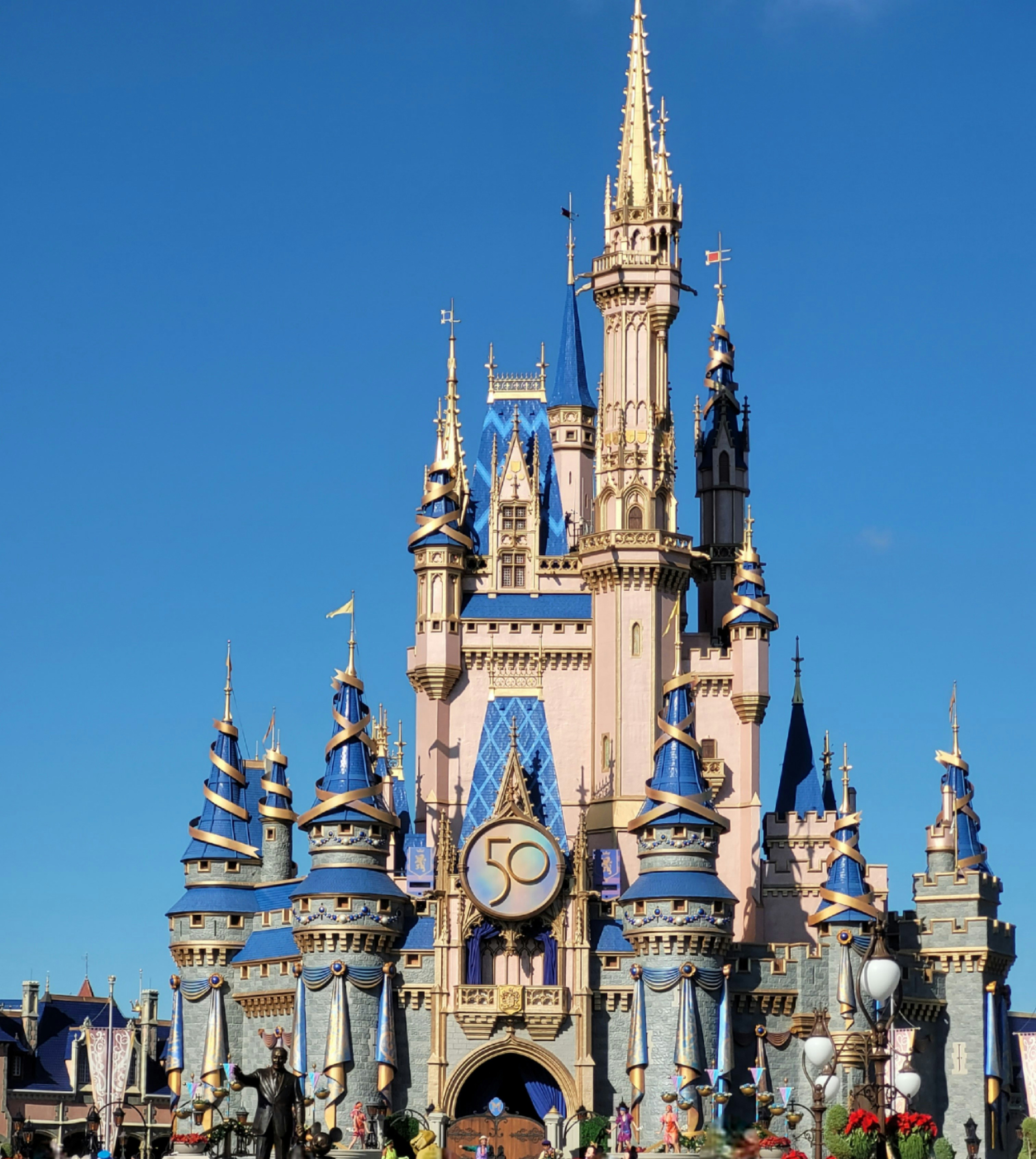 Iconic fairy tale castle adorned with blue and gold accents, celebrating its 50th anniversary with a prominent emblem at the entrance.