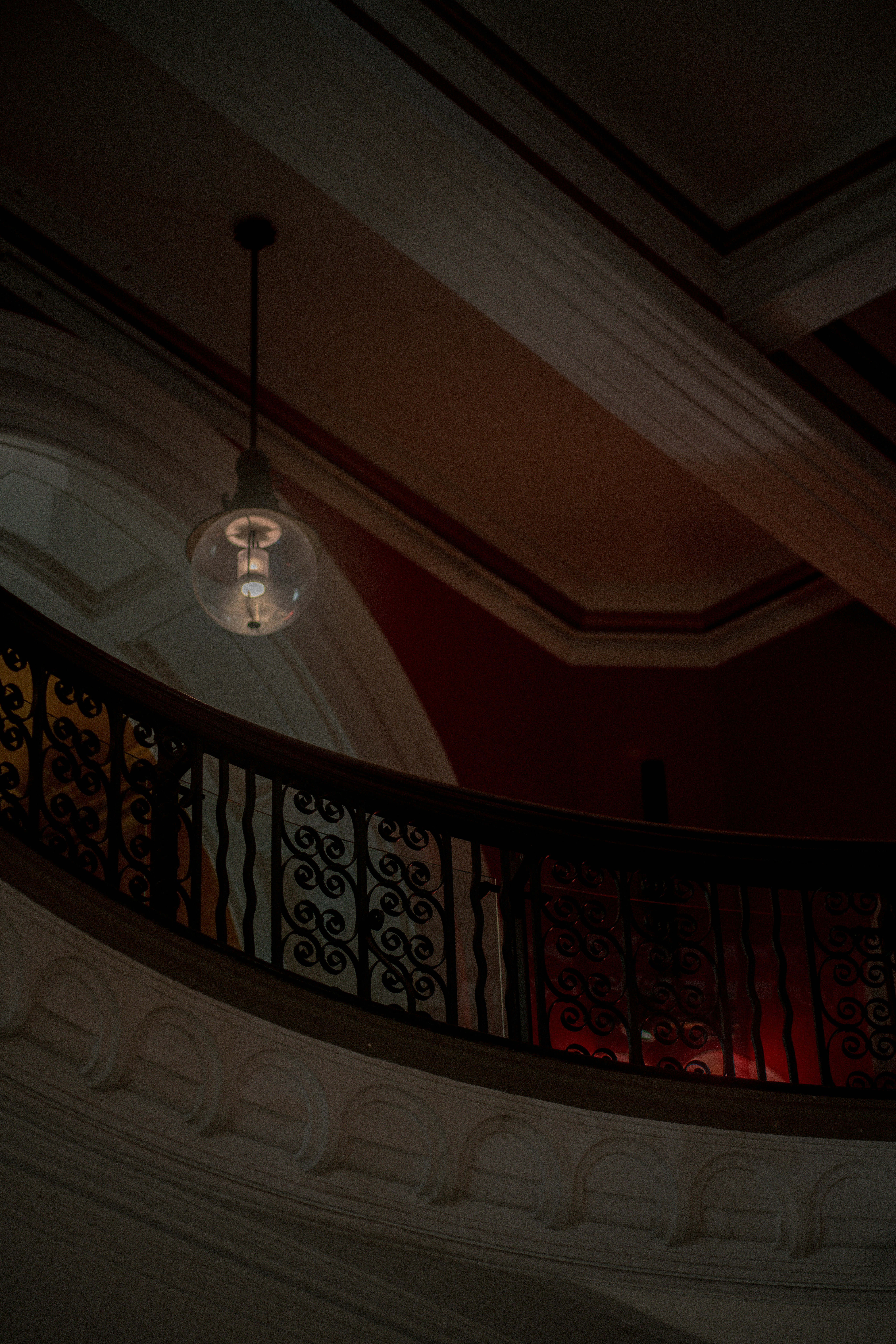 Midnight Lobby Glow: A solitary bulb above ornate balcony curves