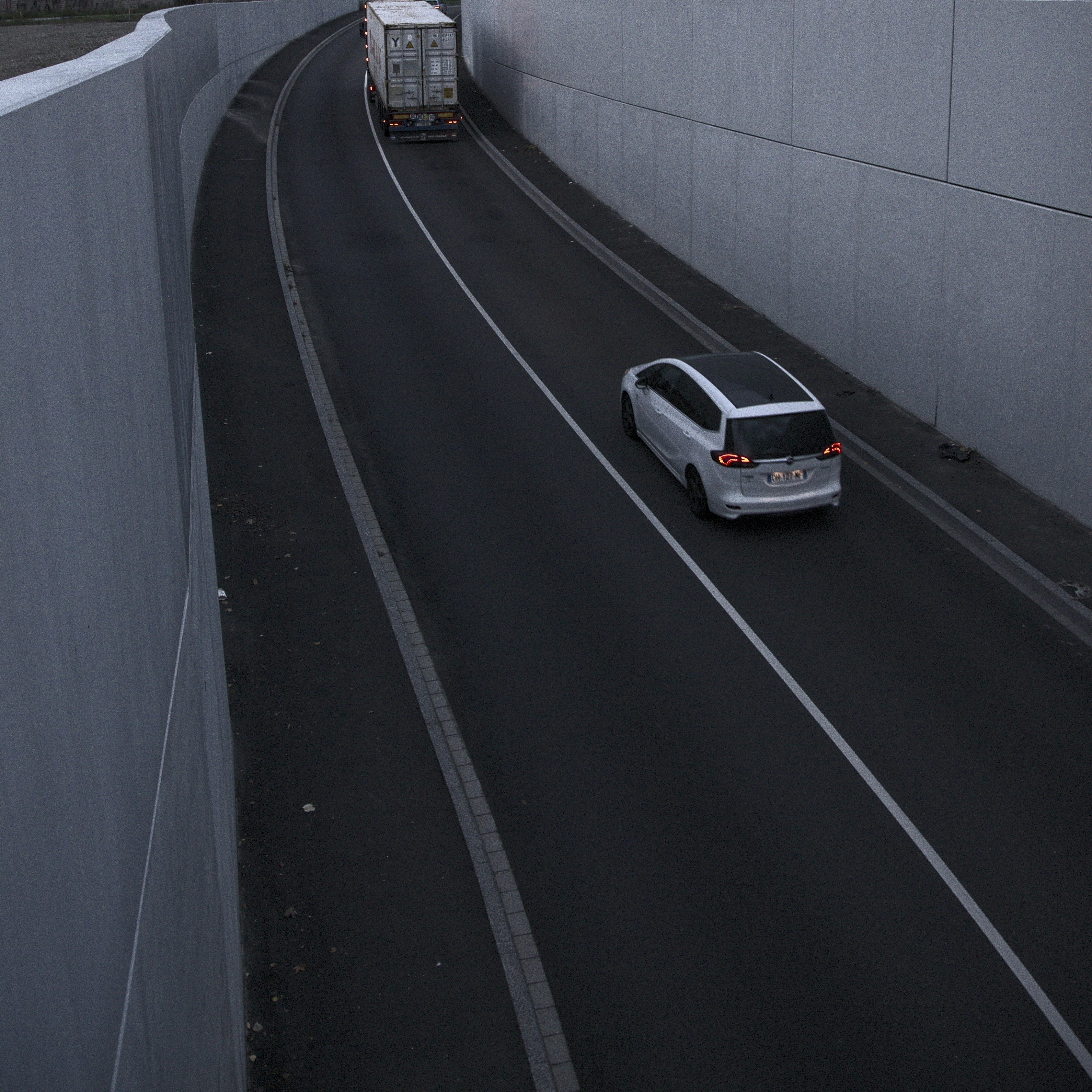 a car driving down a road next to a wall
