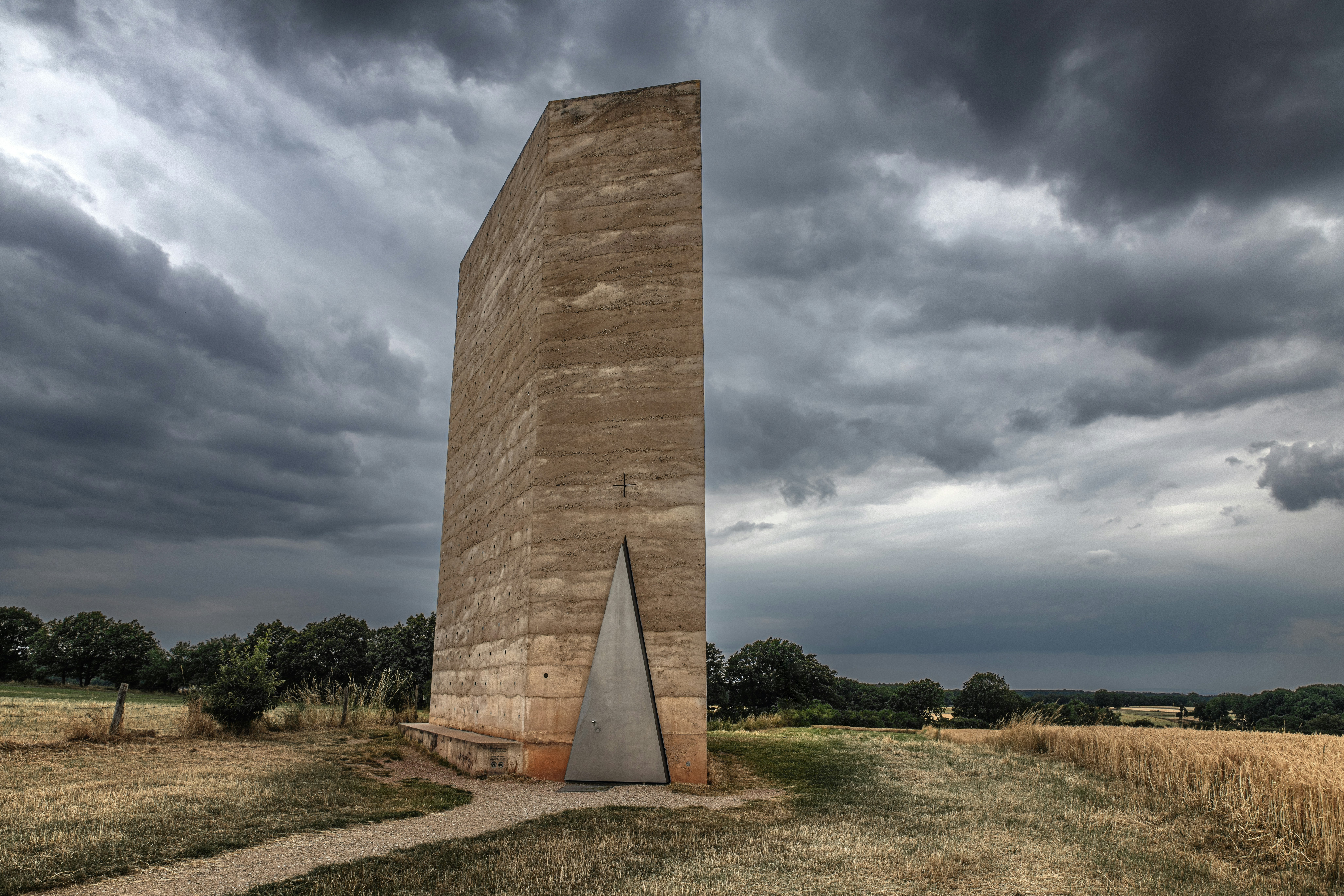 A tall stone monument sitting in the middle of a field photo – Free ...