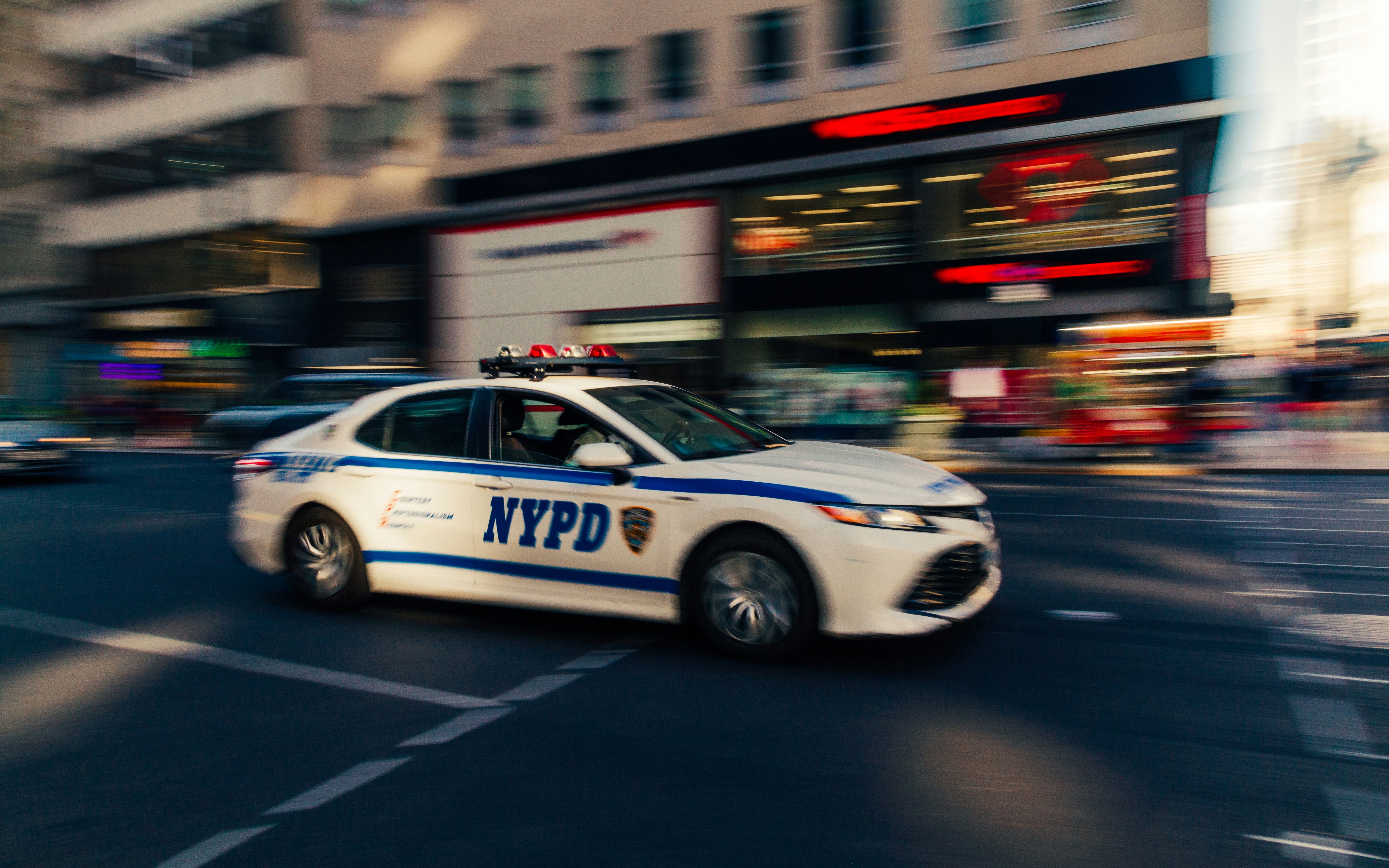 A police car driving down a city street photo – Free New york Image on ...