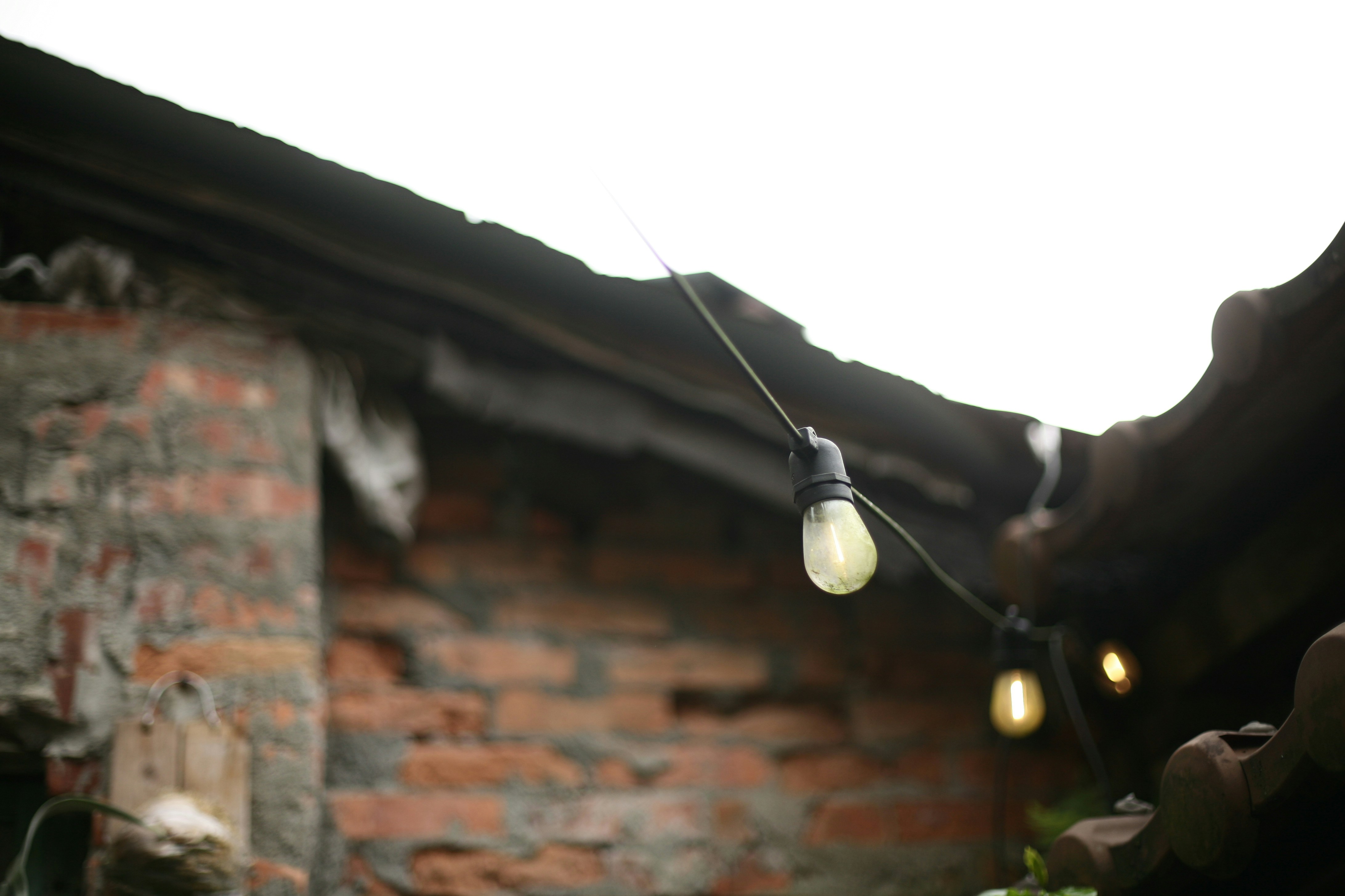 A Lone Bulb Sheds Warm Light Over a Weathered Brick Courtyard
