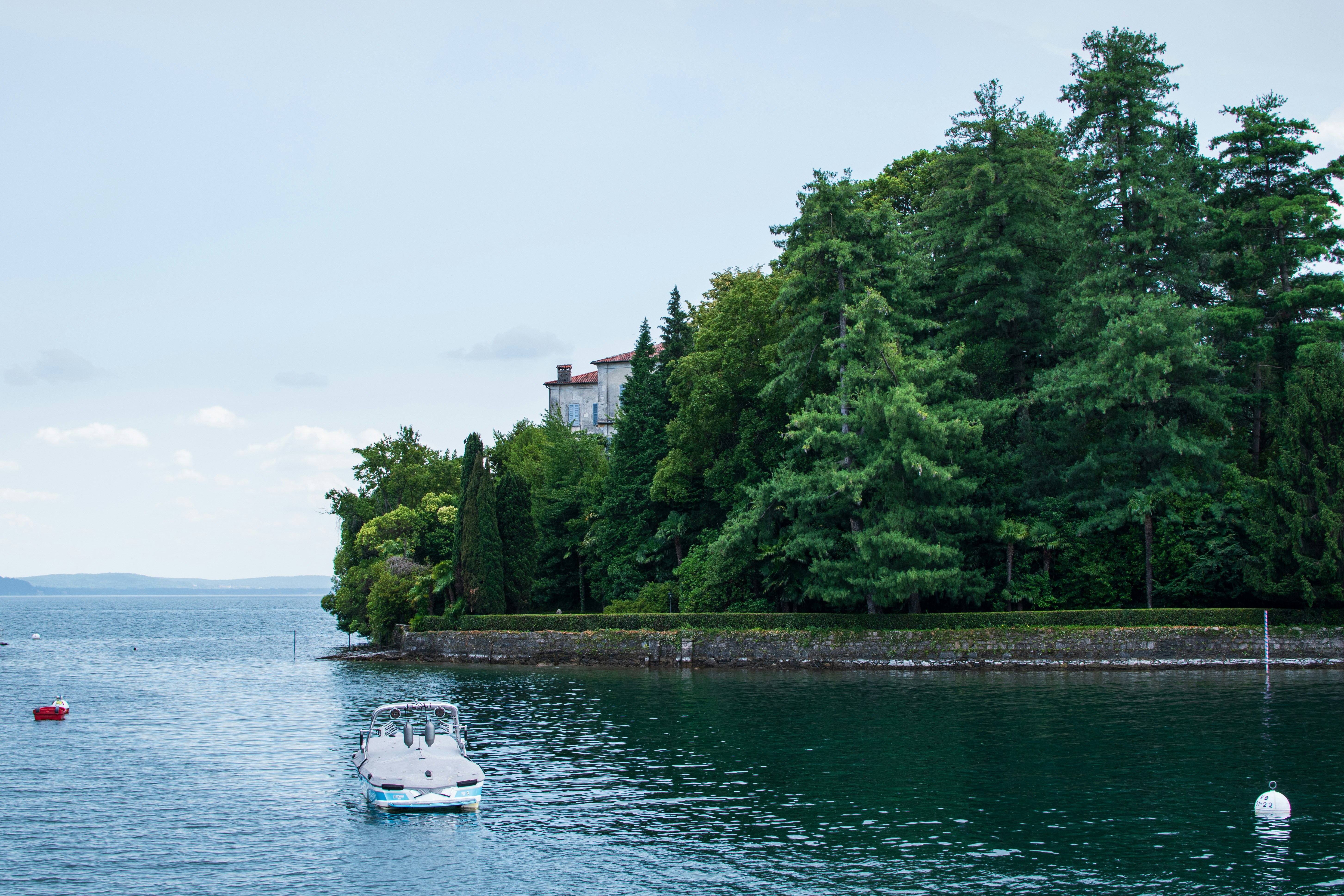 Boat at Verdant Harbor: Quiet Waters by a Cliffside Estate