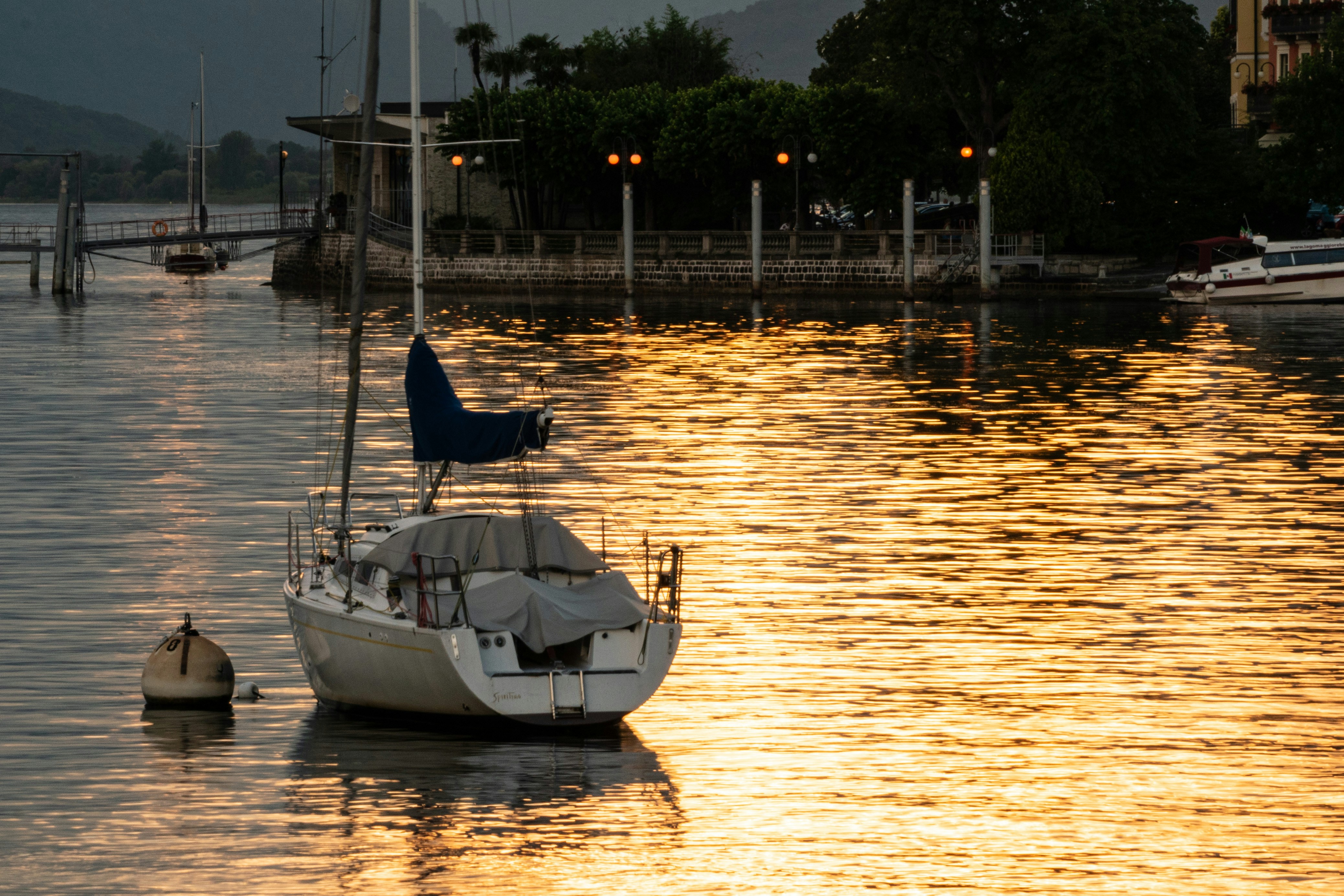 Amber Stillness: A Sailboat Framed by Dusk on Calmed Waters
