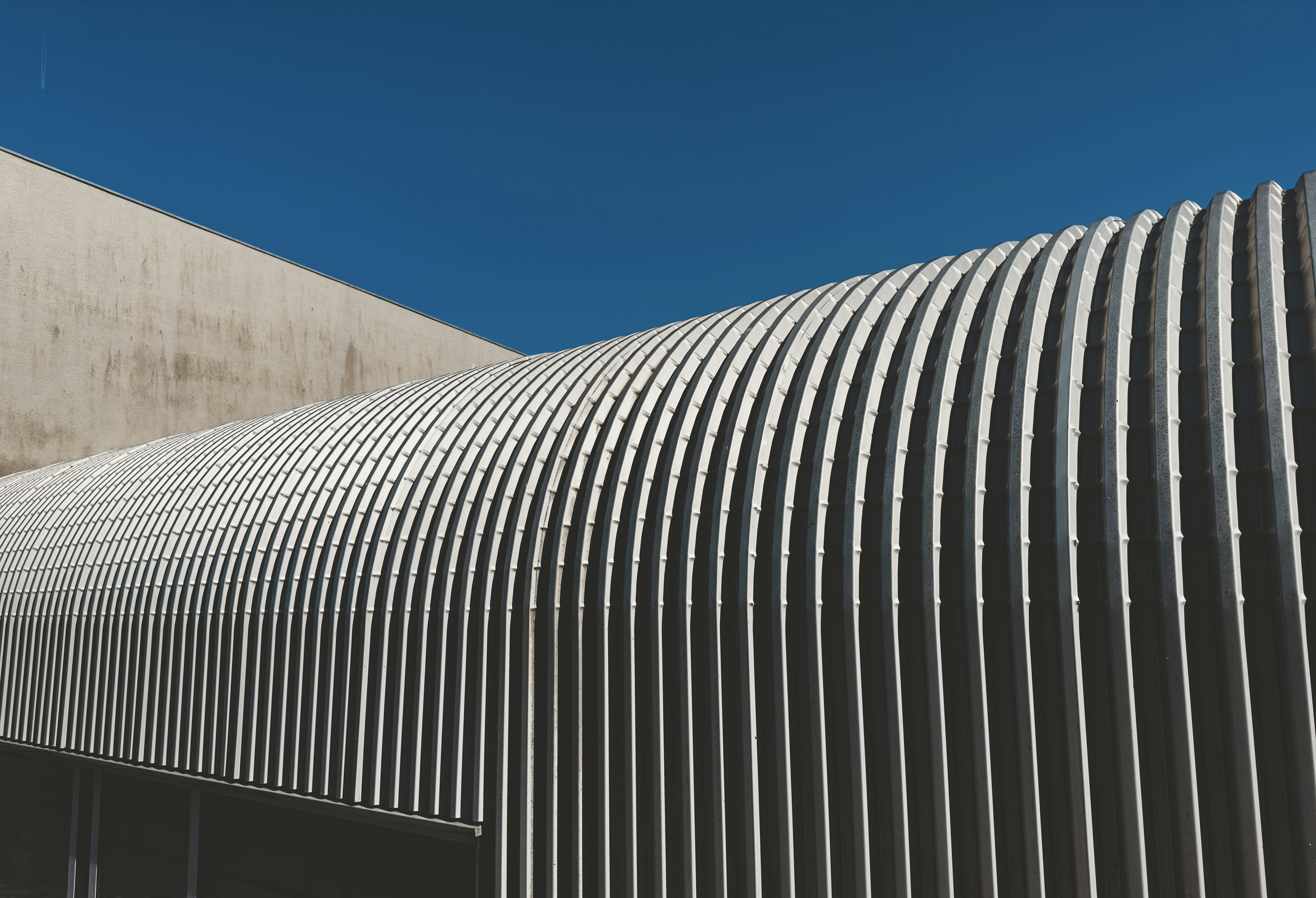 A building with a curved metal structure on top of it photo – Free ...