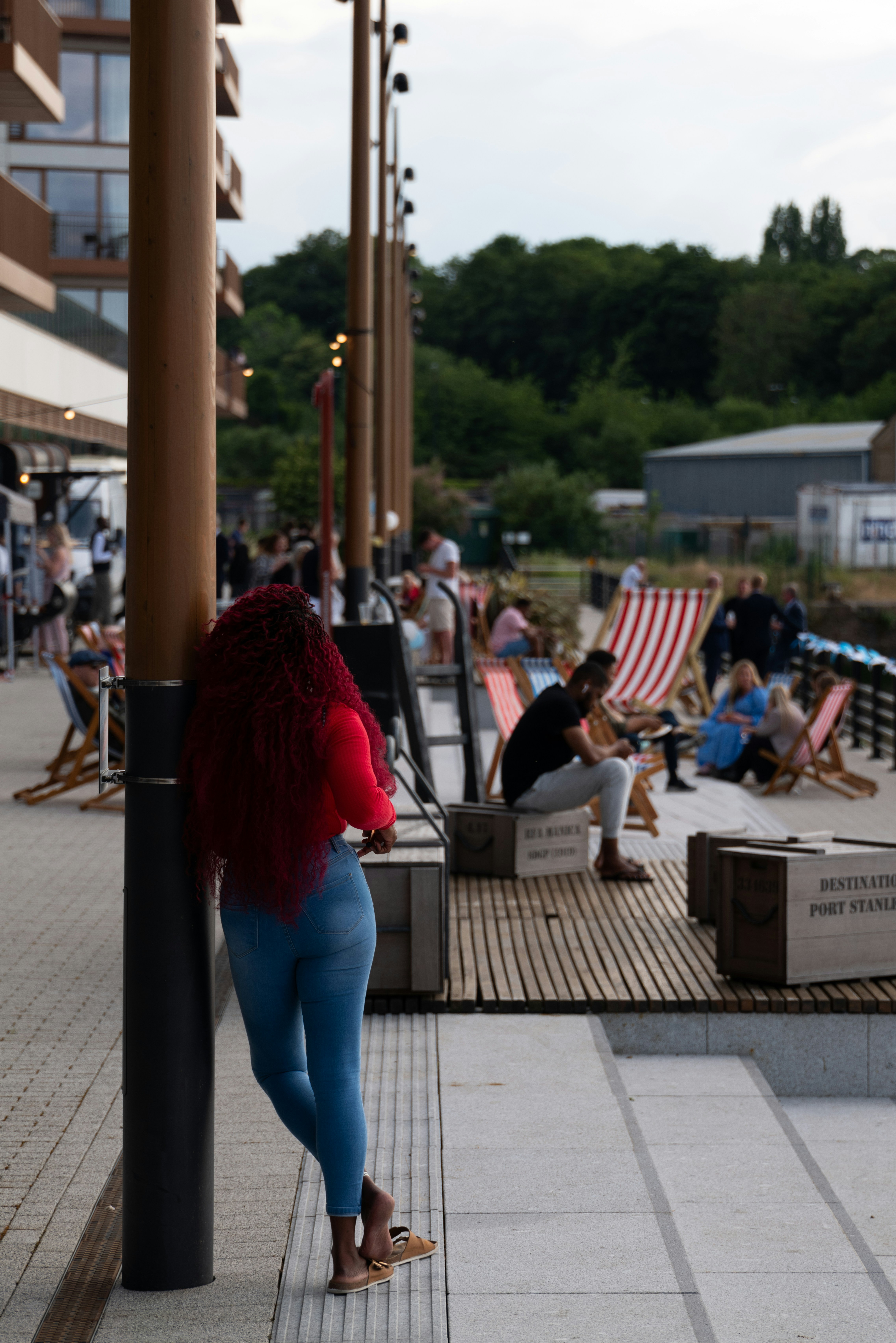 A woman leaning against a pole on a boardwalk photo – Free Woman Image ...