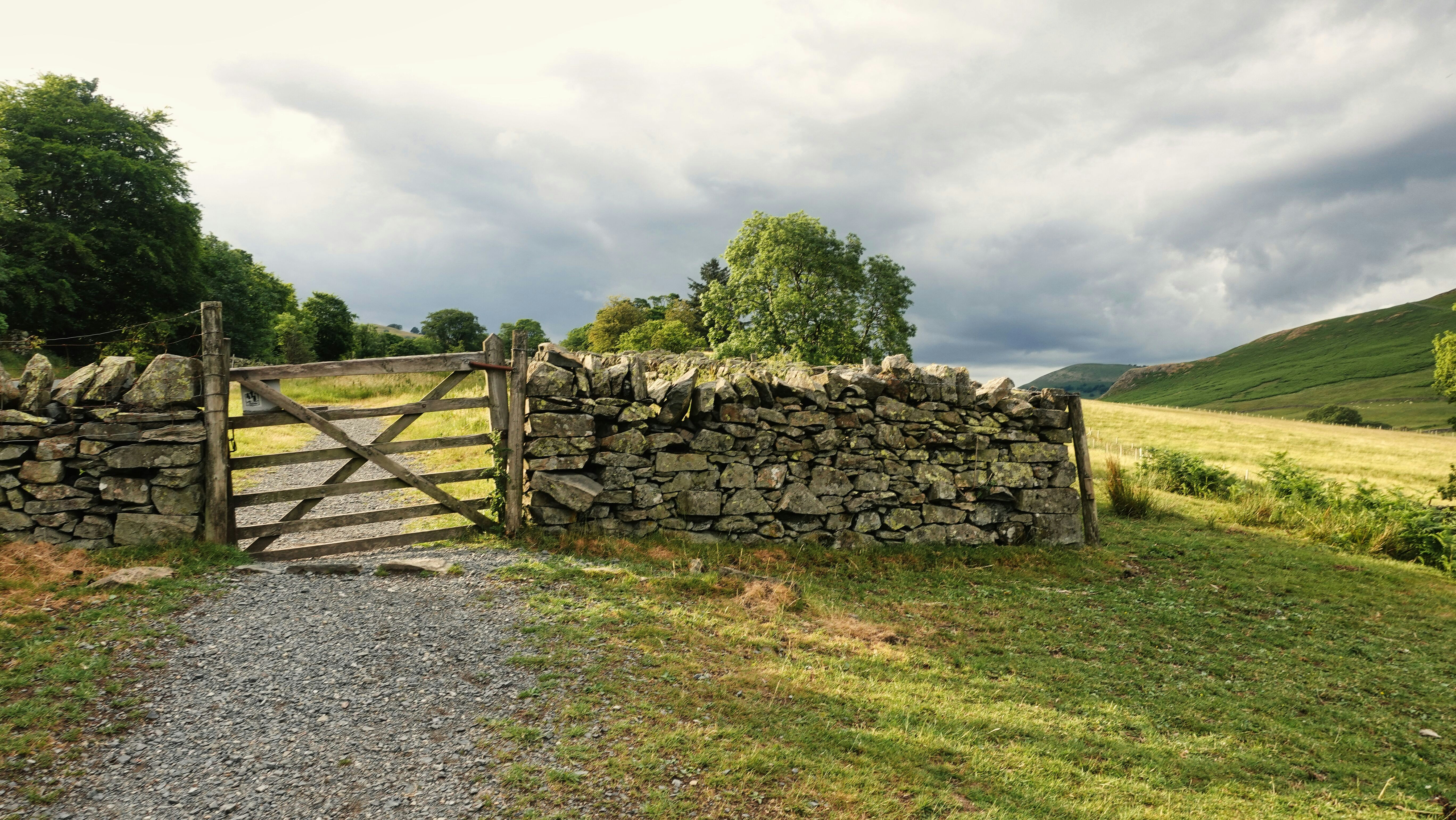 a stone wall and gate in a grassy field