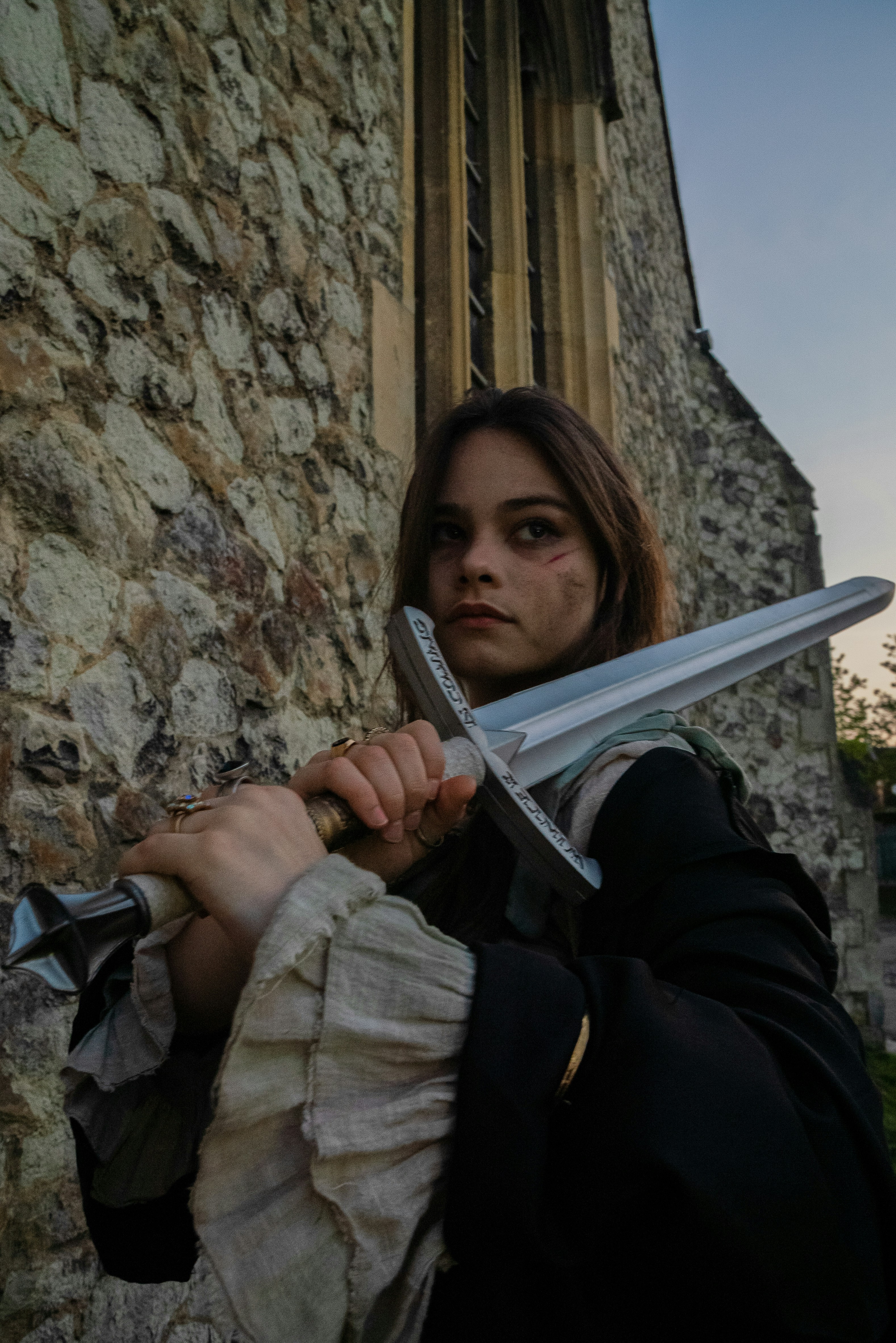 A woman holding a sword in front of a stone building photo – Free ...