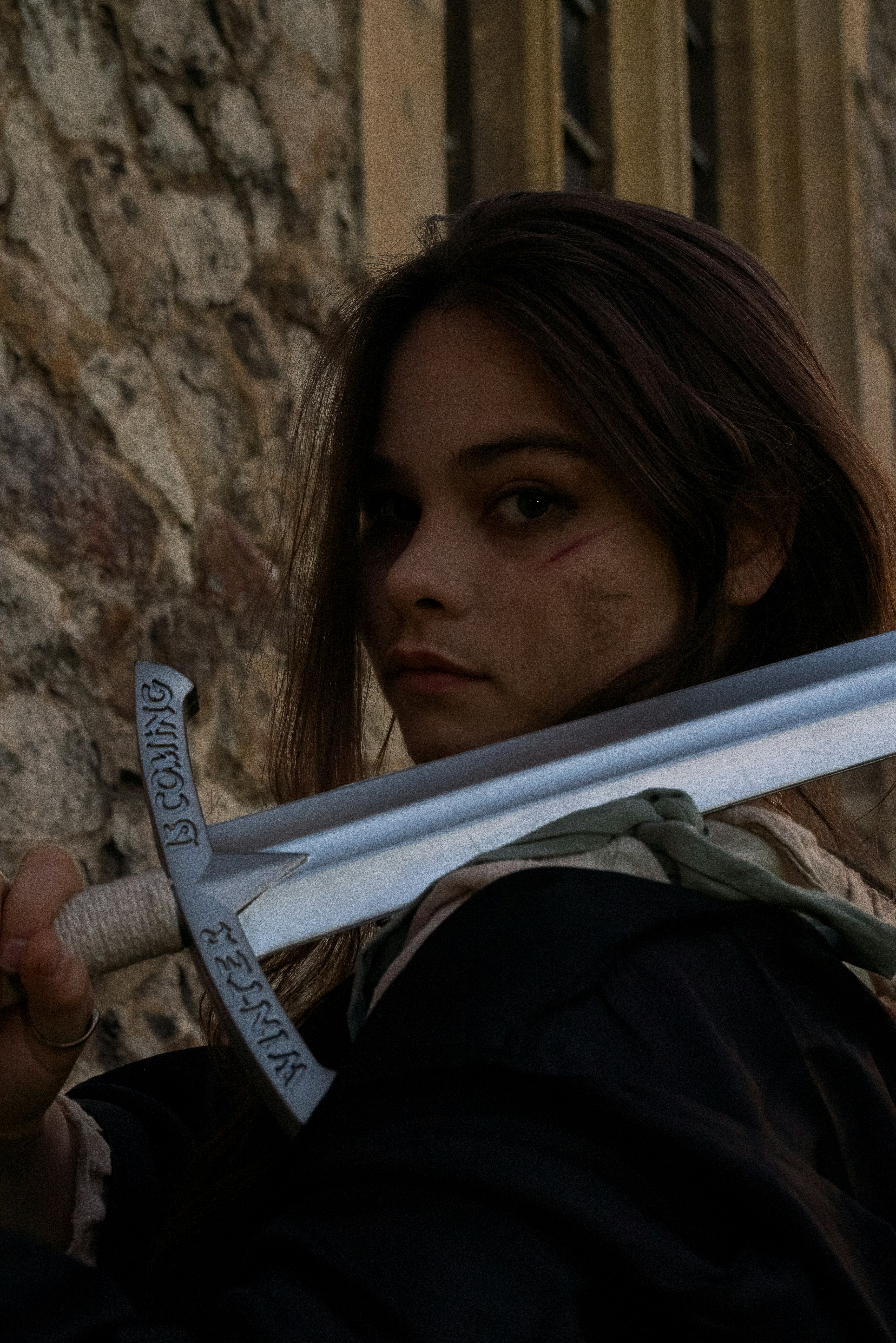 A woman holding a sword in front of a stone building photo – Free Sword ...