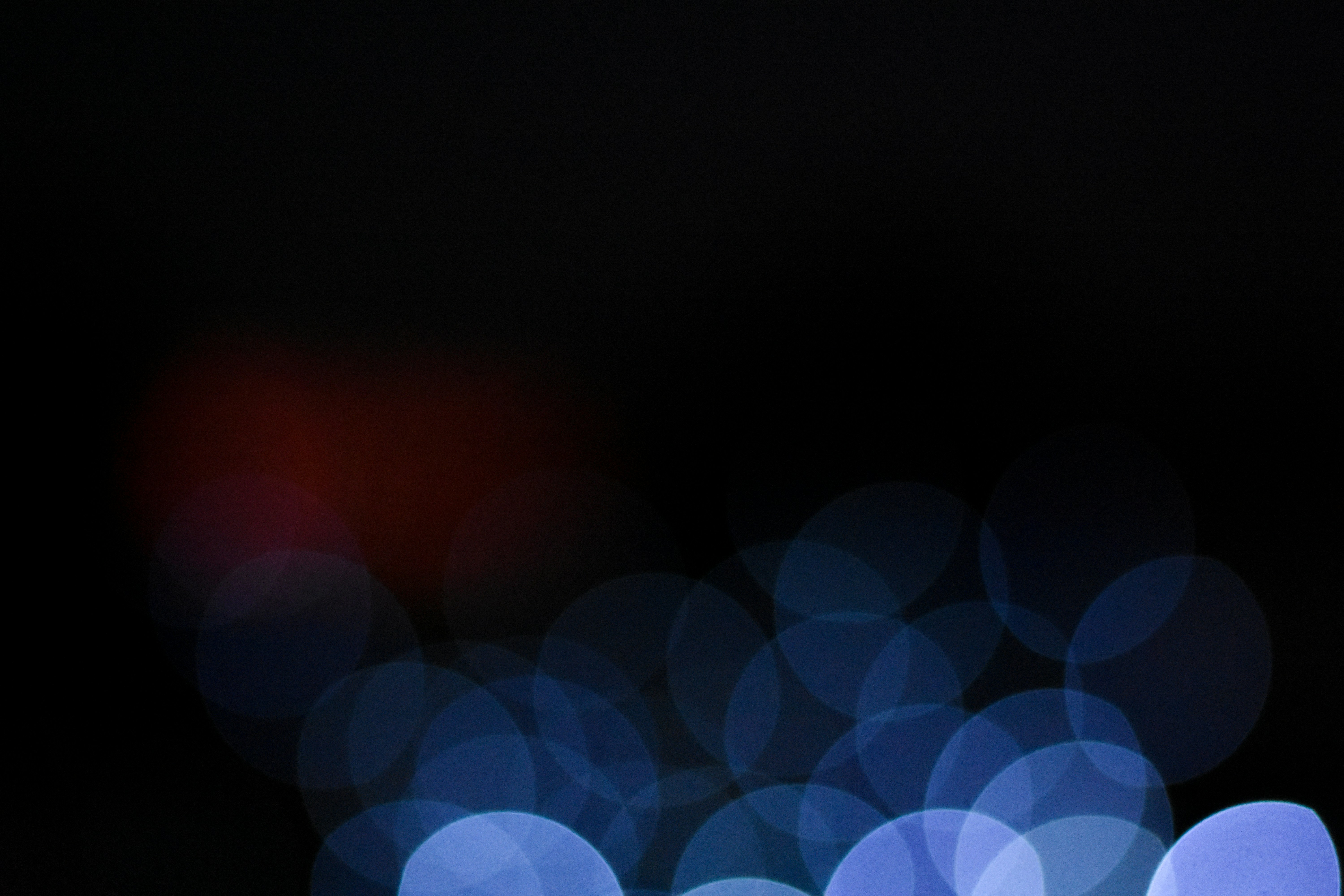 Abstract bokeh composition featuring soft blue and red orbs against a dark background.