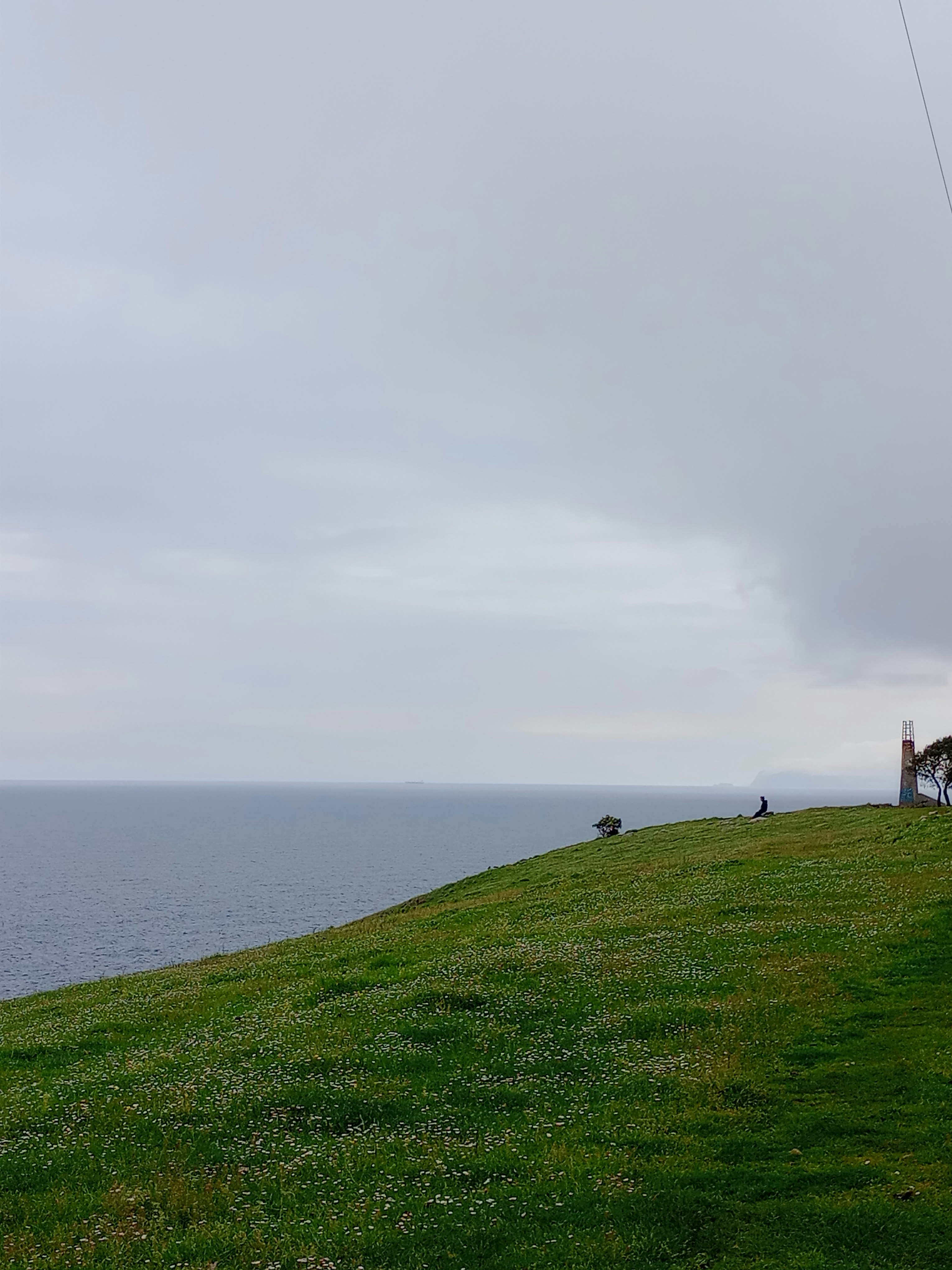 A pilgrim on the Camino del Norte rests and contemplates along the Cantabrian coastline near Pobena, Spain.