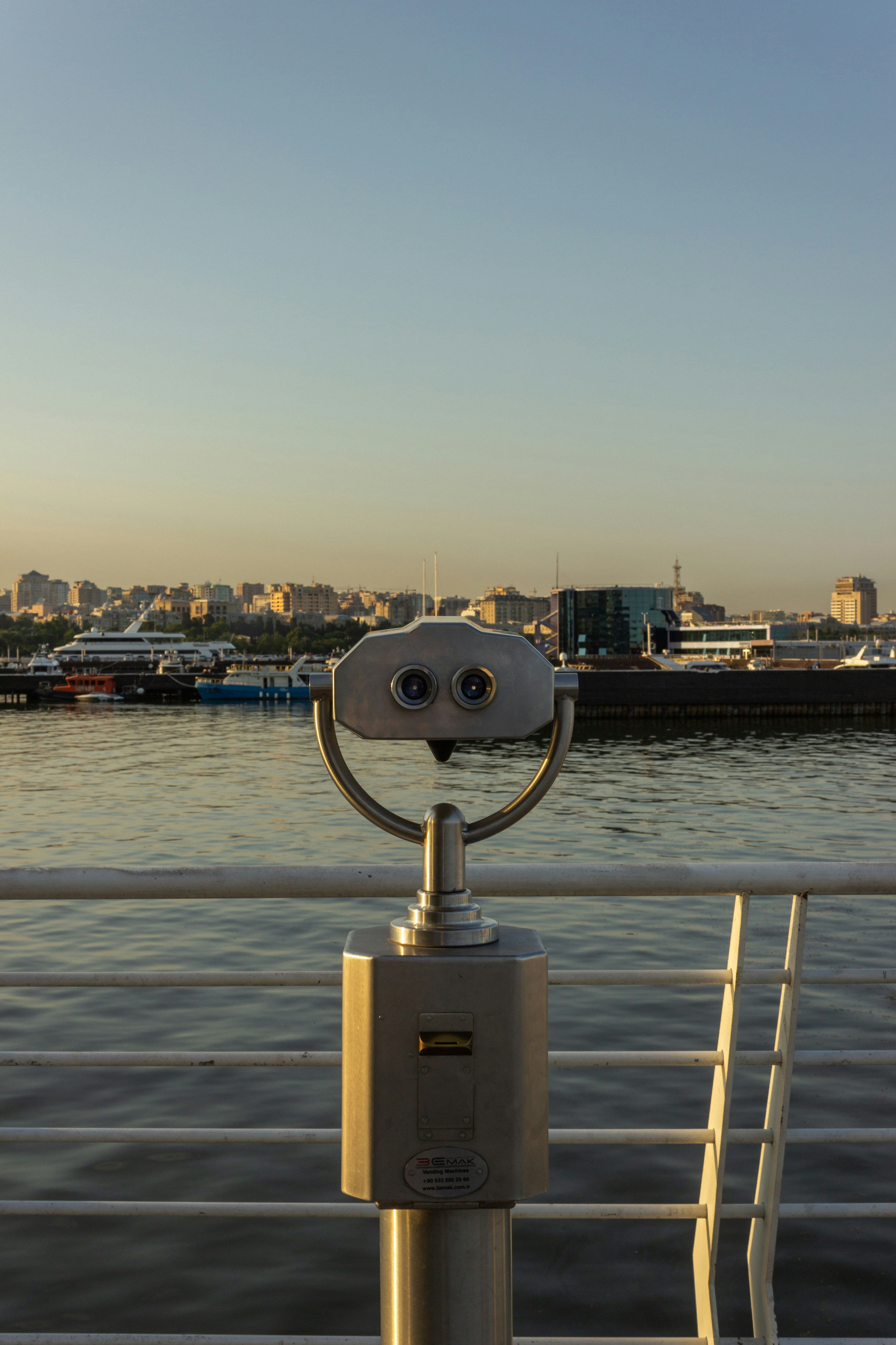 Harbor Gaze: City Framed by a Pierside Binocular Viewer at Dusk