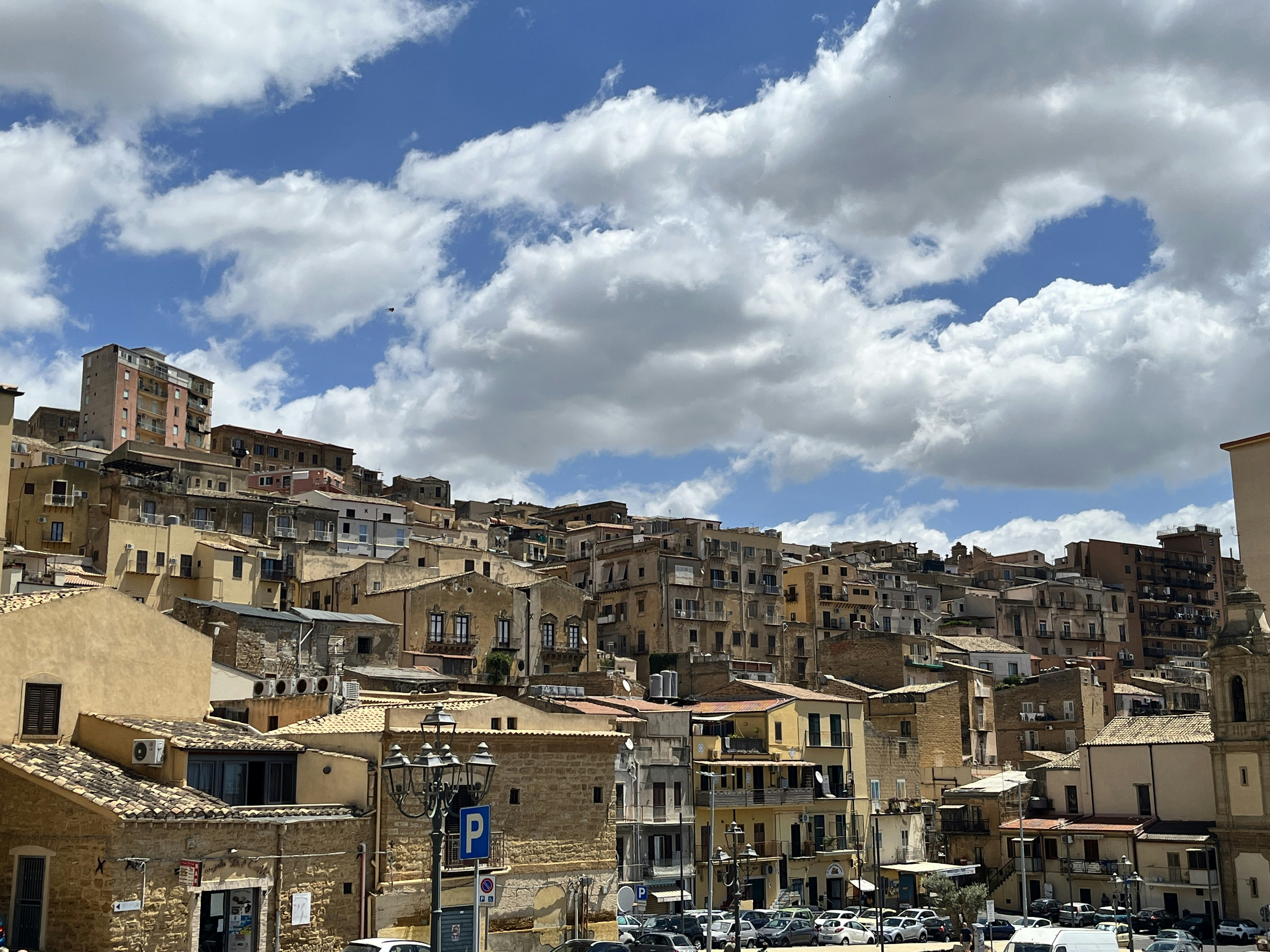 Historic hillside townscape under a vibrant sky with scattered clouds.