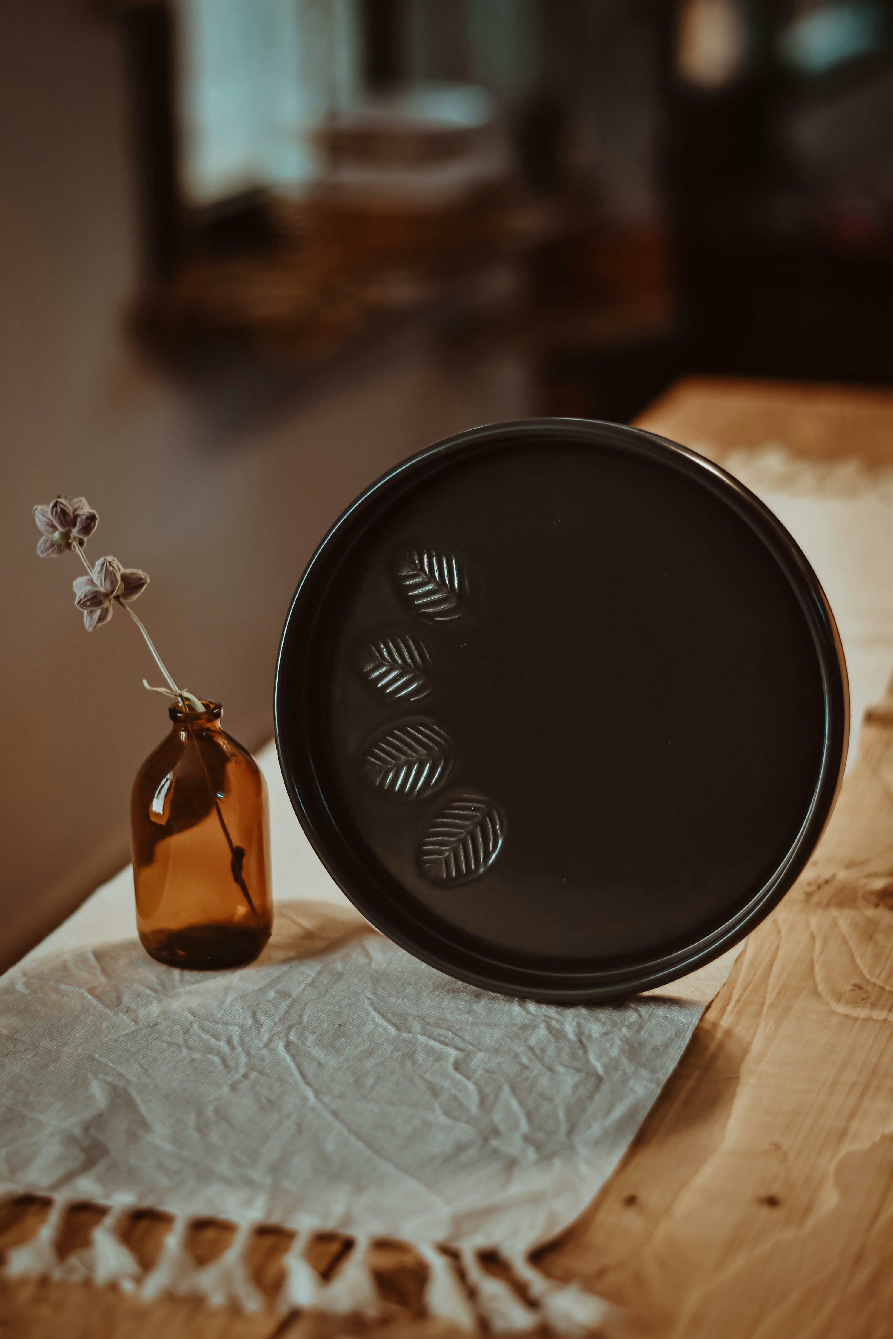 Earthen amber vase and circular lens cap: still life on a sunlit table