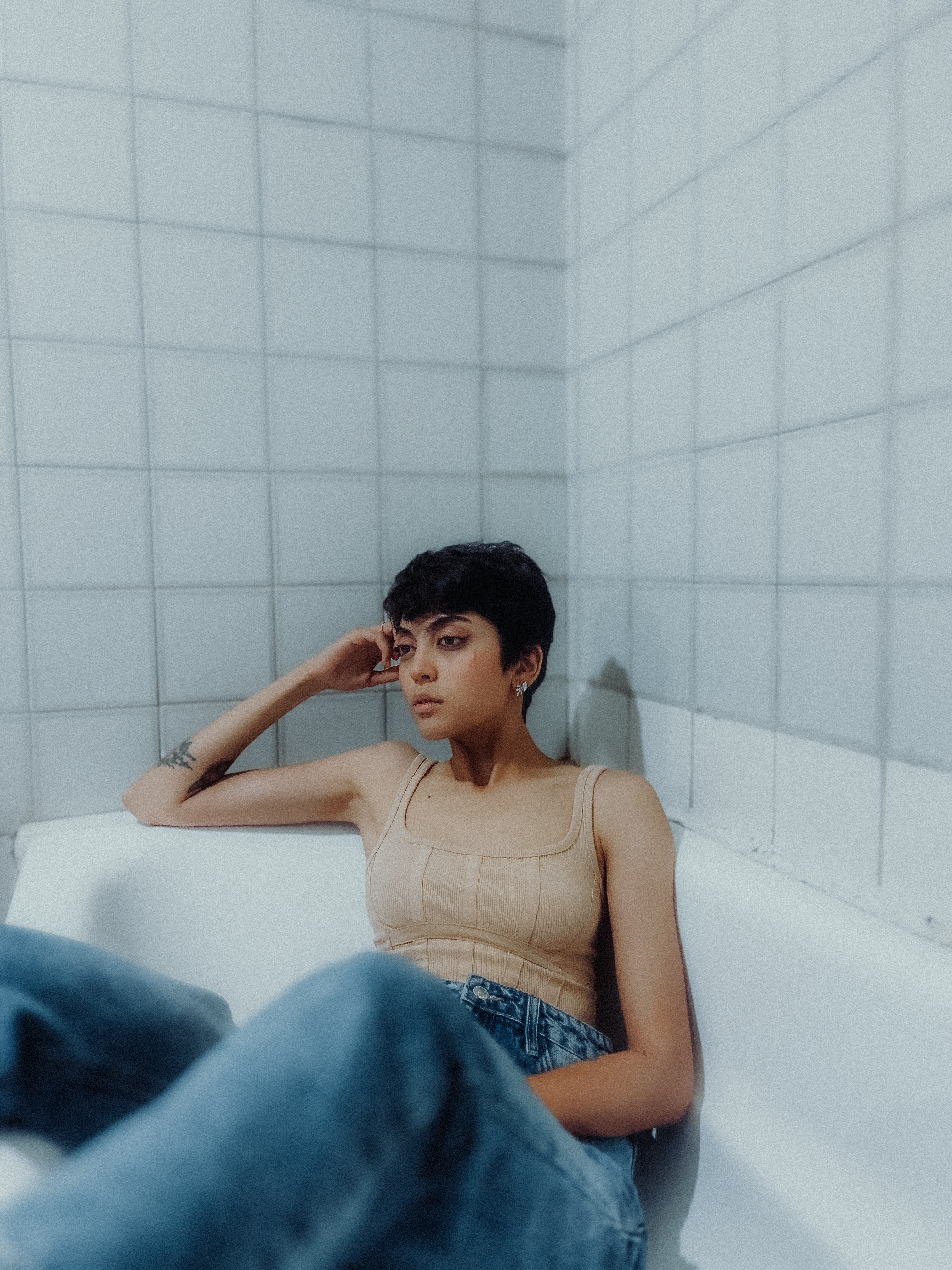 a woman sitting in a bathtub with her hand on her head