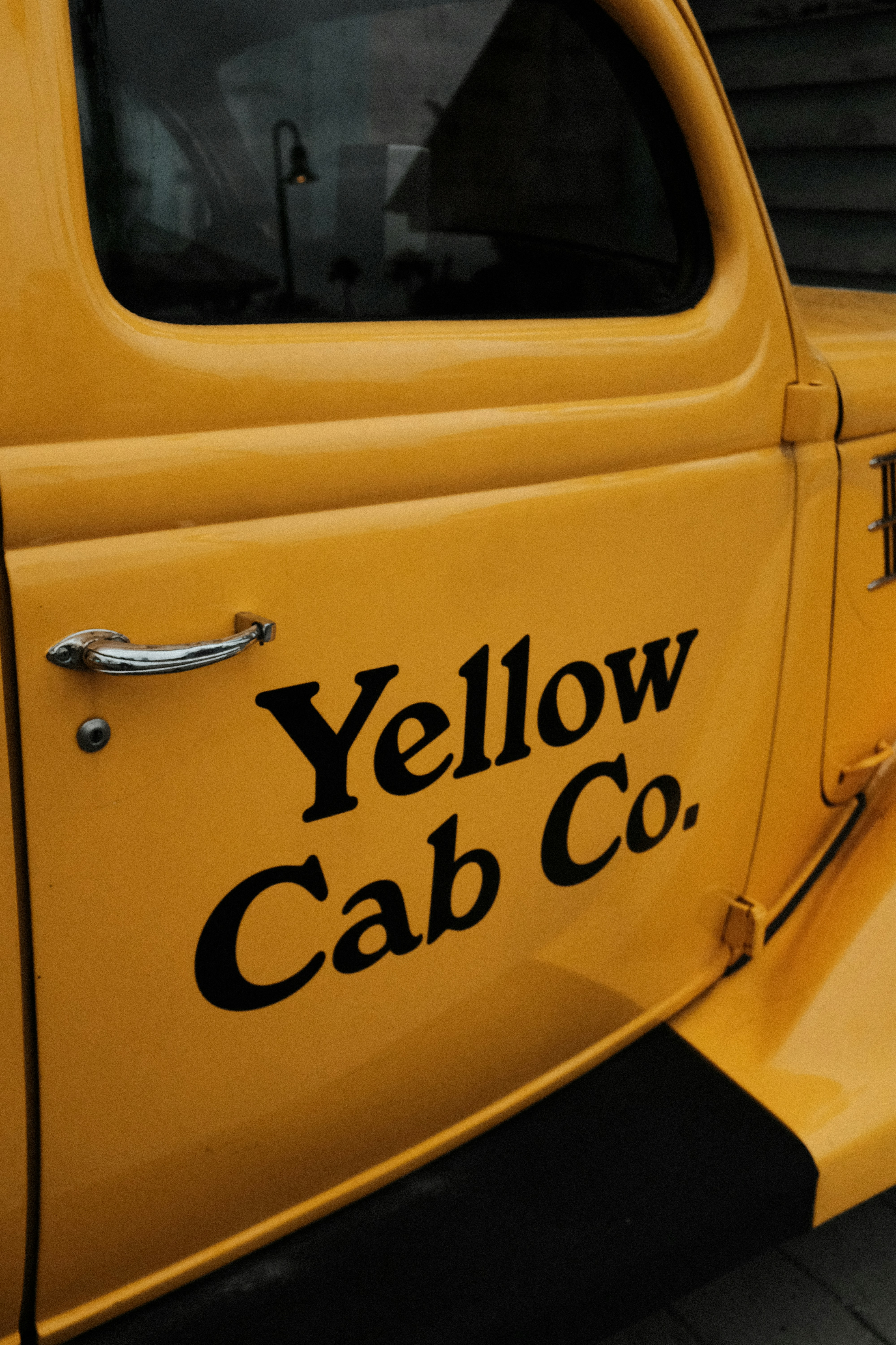 Sunlit Yellow Cab Door with Prominent Black Logo