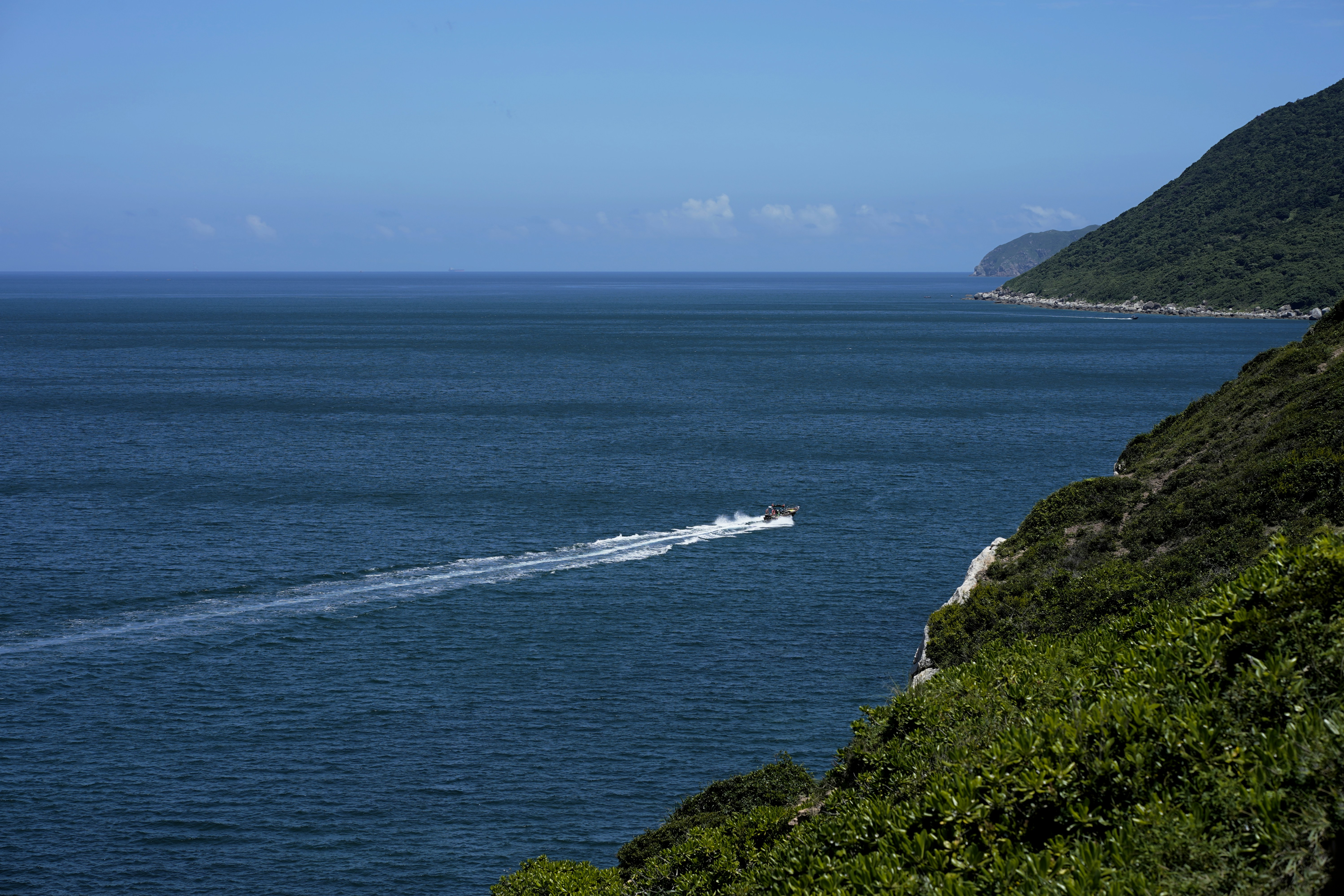 A boat traveling on the ocean near a cliff photo – Free Mirs bay Image ...