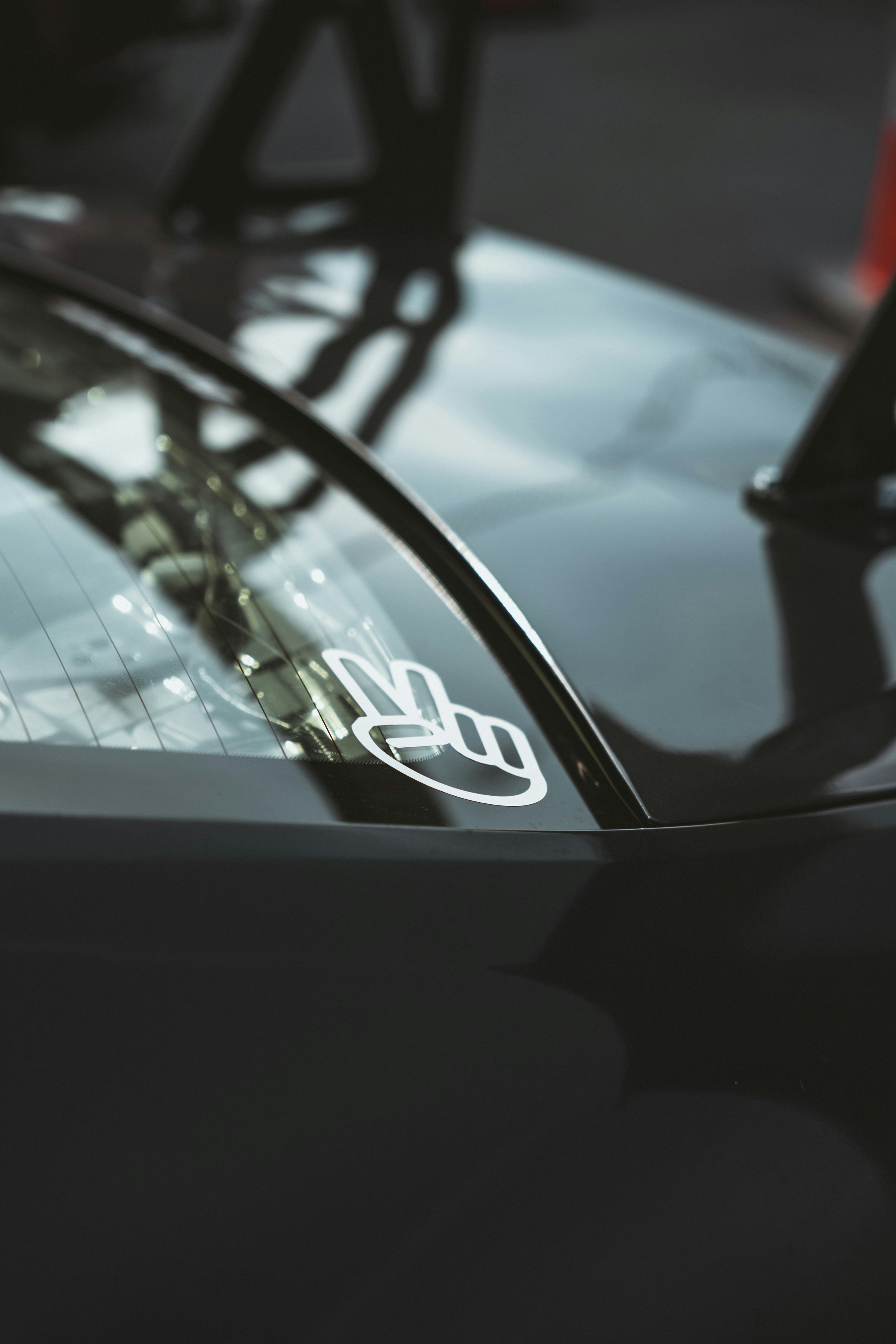 White Peace Sign on a Glossy Car Window at Dusk