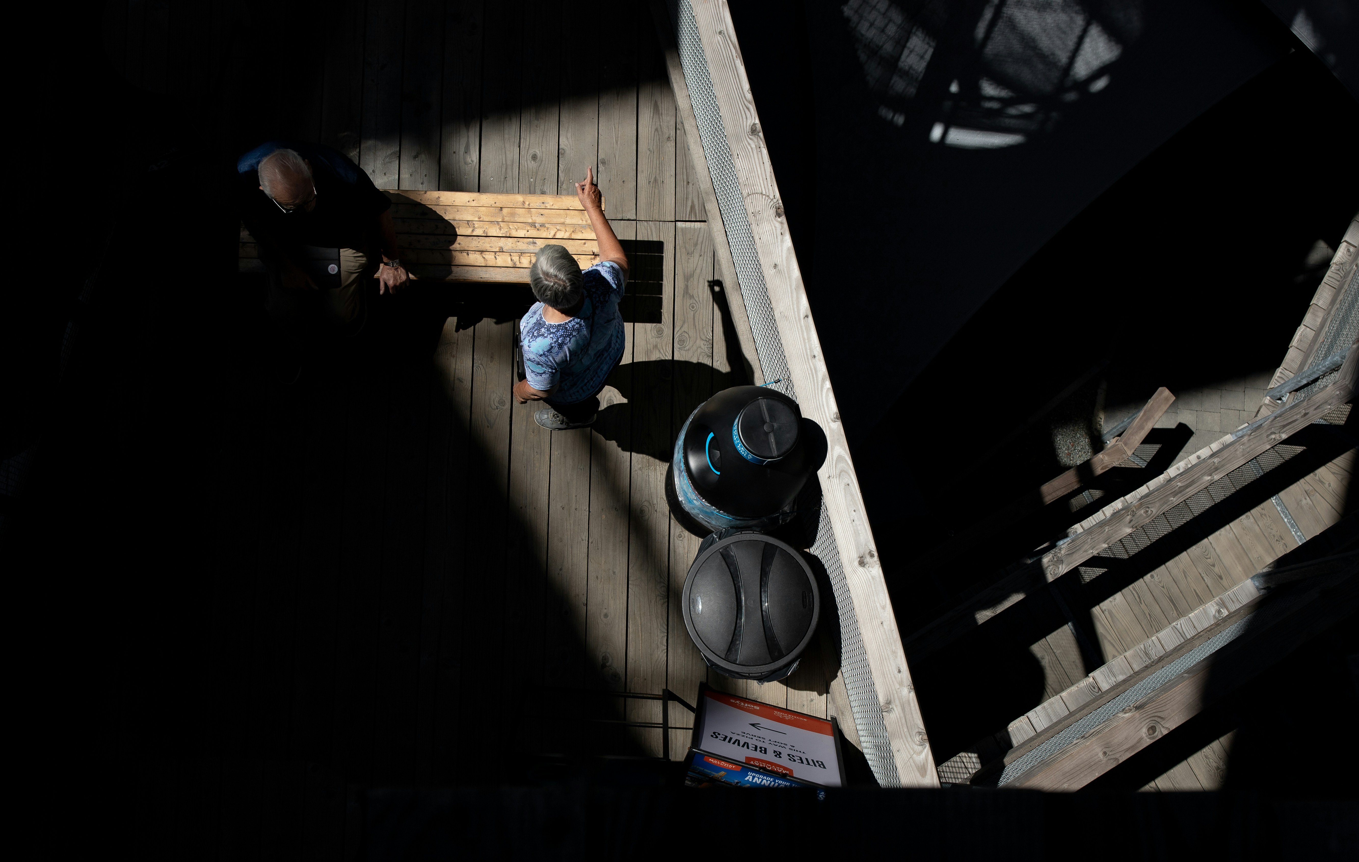 Sun-Dappled Rooftop Deck: A Quiet Overhead Moment Between Two Figures