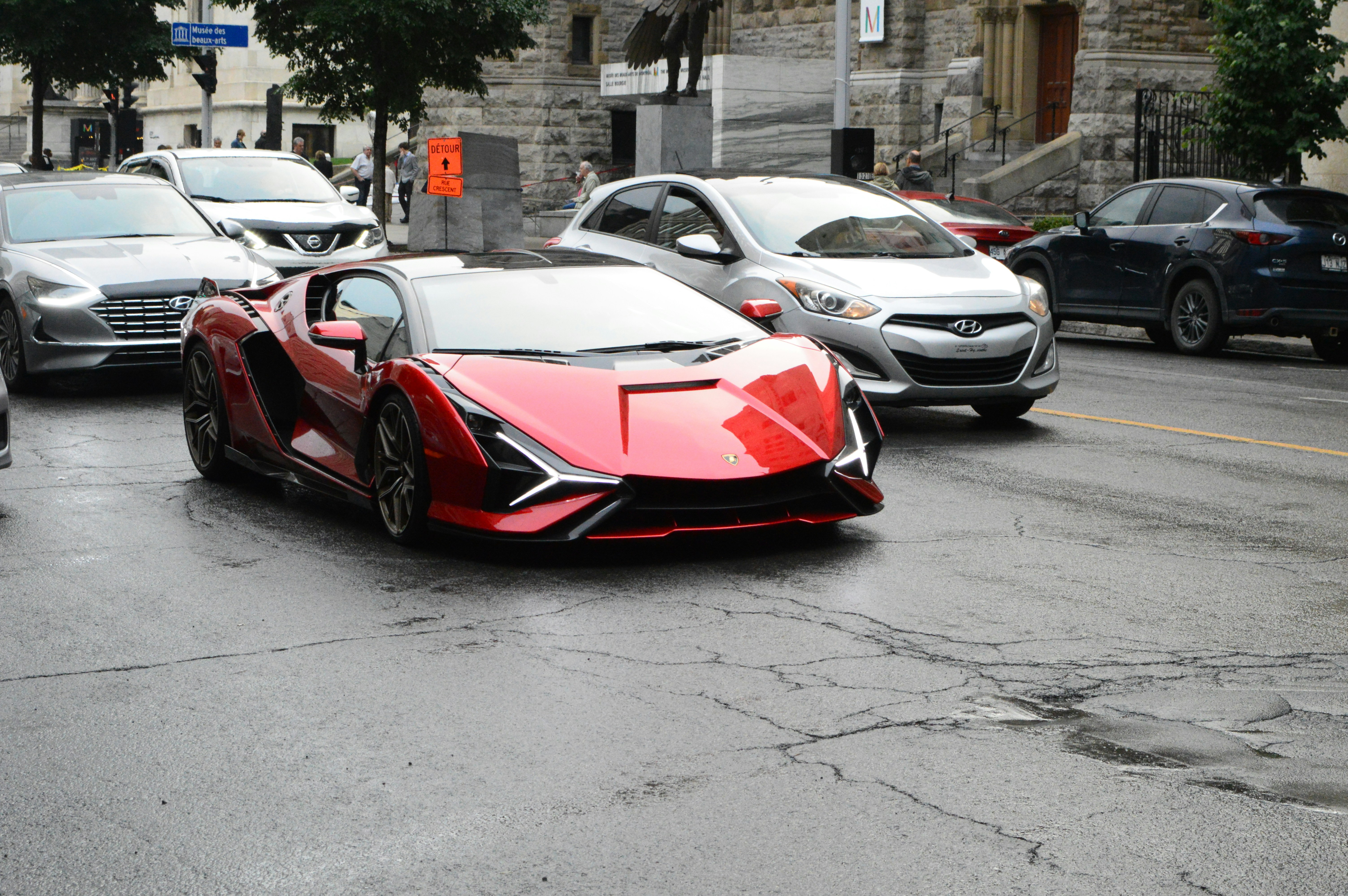 Foto Un auto deportivo rojo conduciendo por una calle junto a autos ...