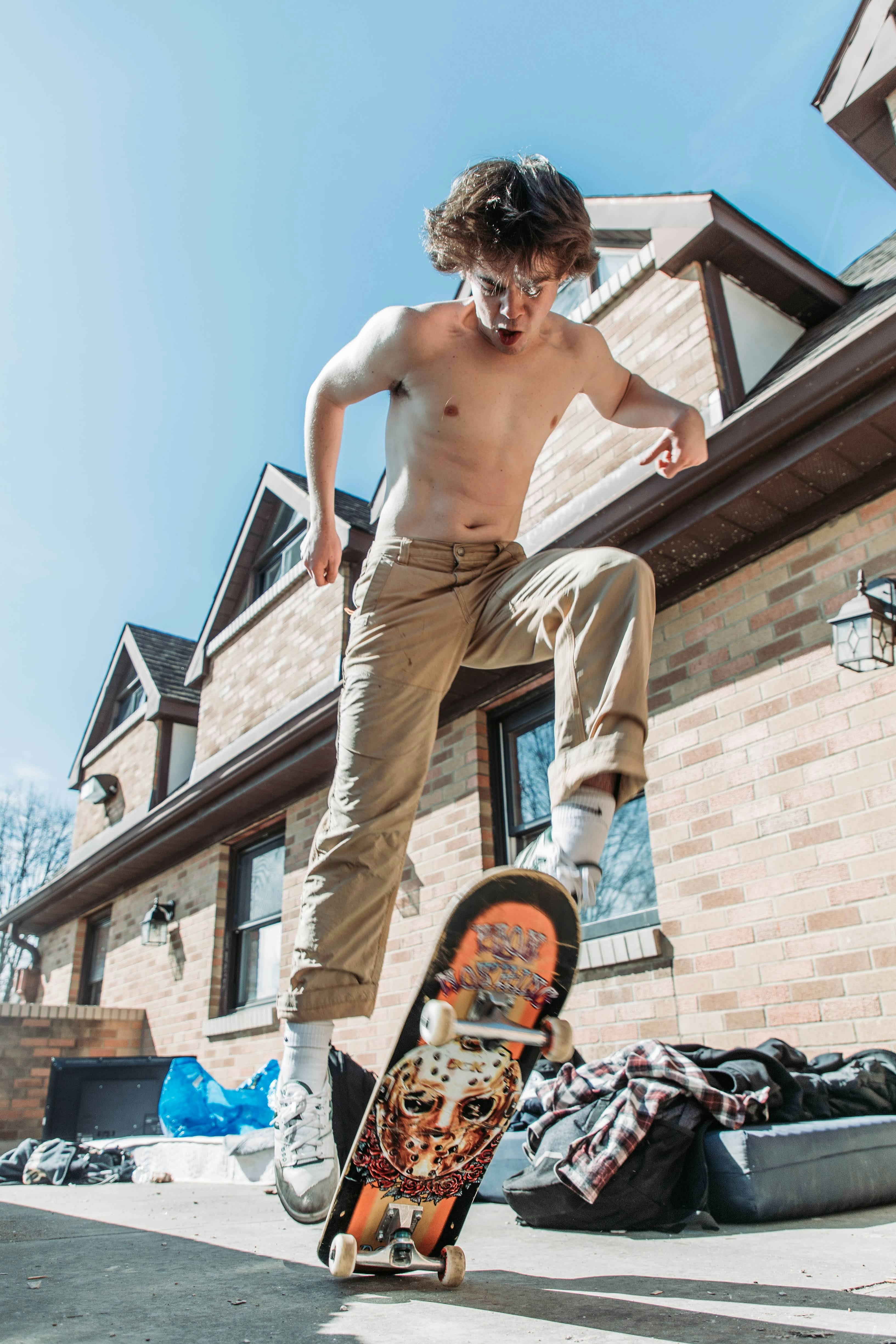 A shirtless man riding a skateboard in front of a house photo – Free ...