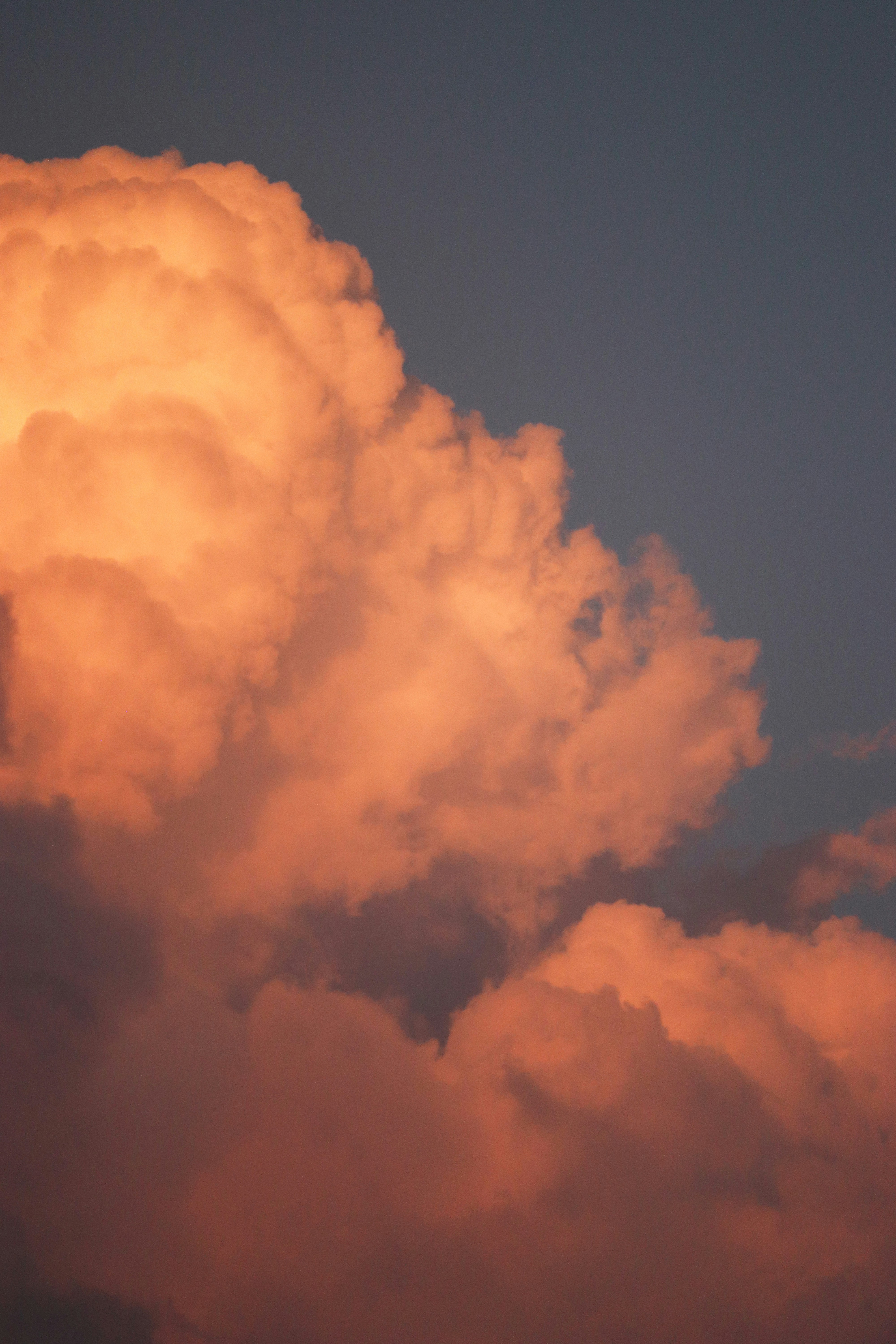 a plane flying through a cloudy sky at sunset