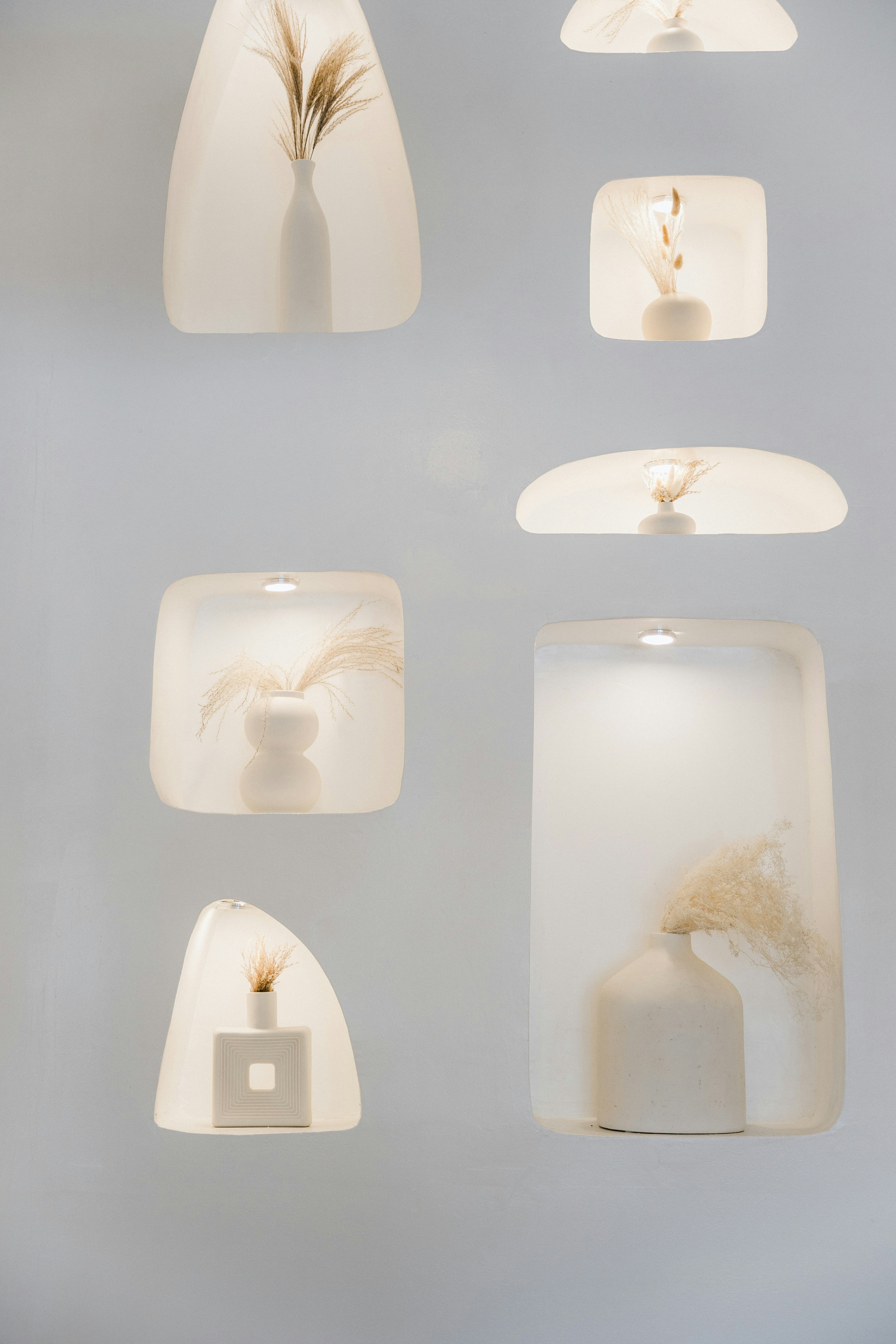 Softly Lit Niches: White Ceramic Vases in a Calm Off-White Display
