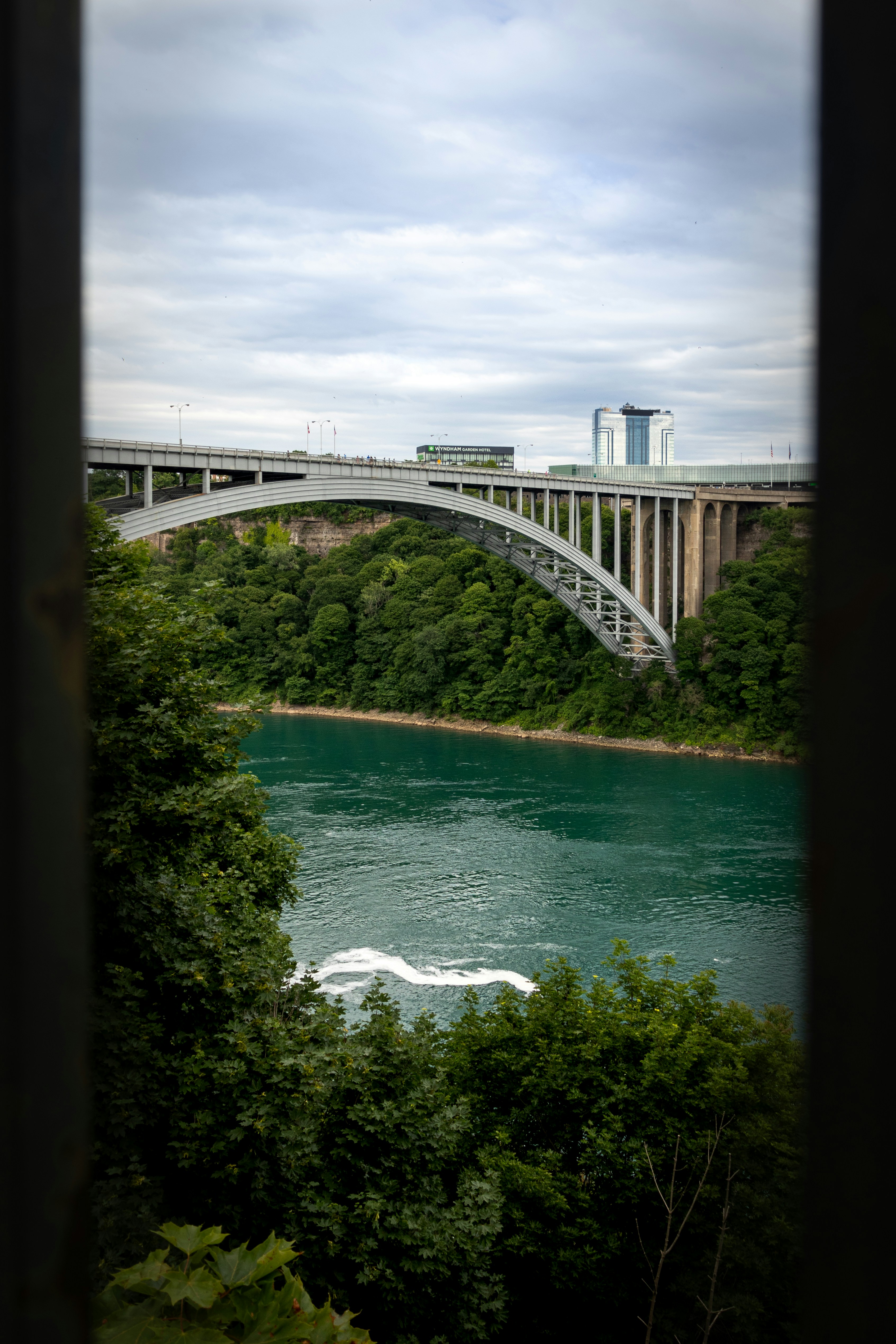 Arc of Steel Over Emerald Waters: A Bridge Framed by Forest