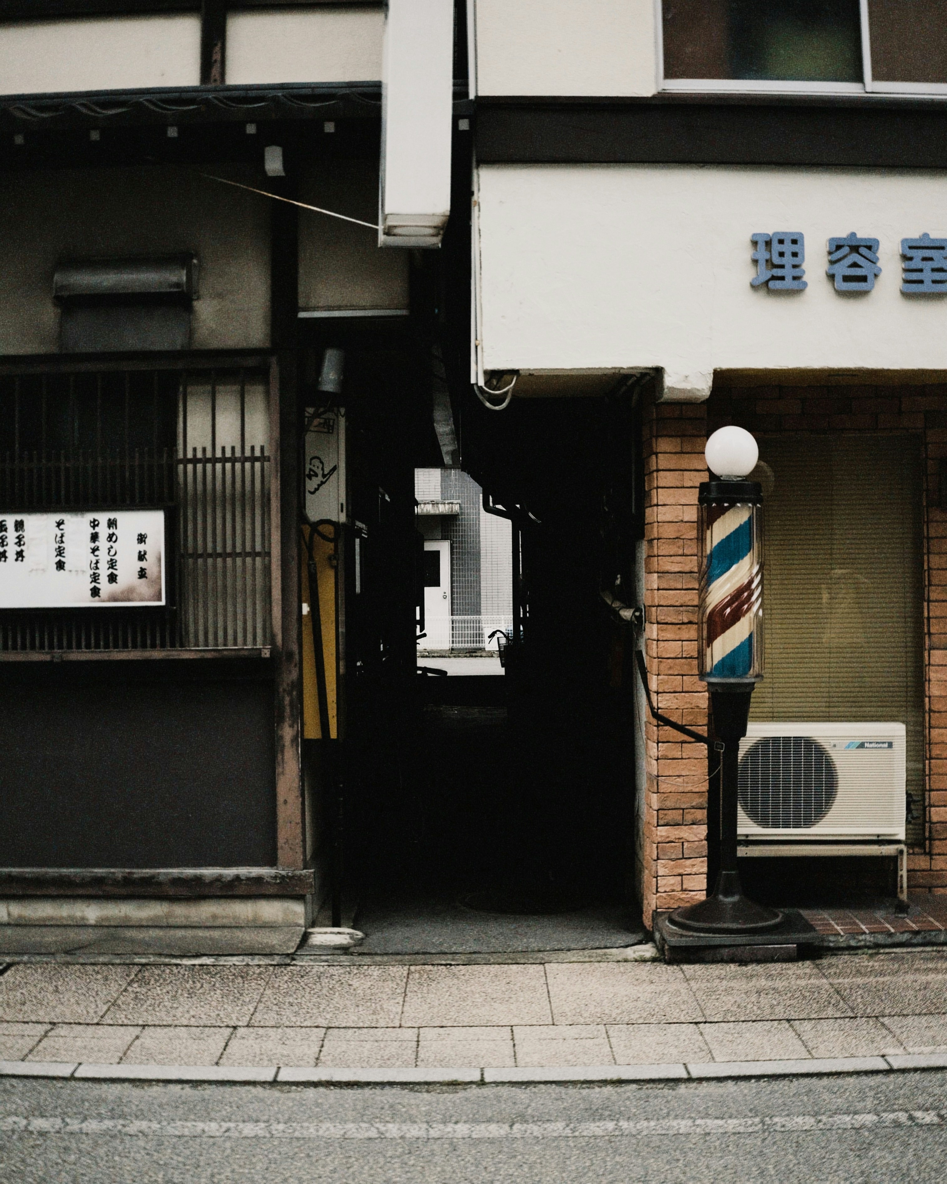Narrow Corridor Between Shops Framed by a Vintage Barber Pole