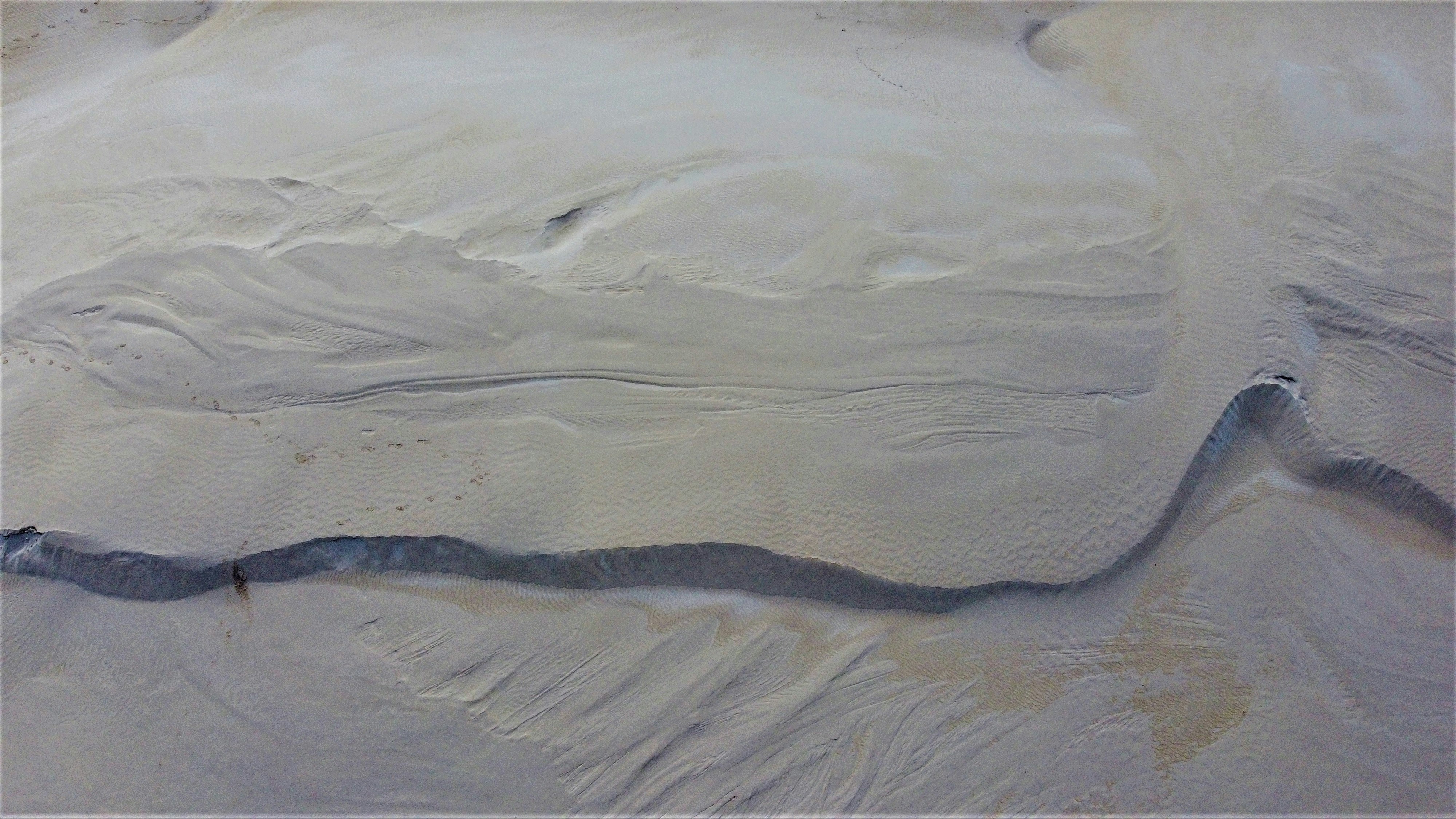 Desert Ribbon: The Wind-Woven Channel Through Pale Dunes