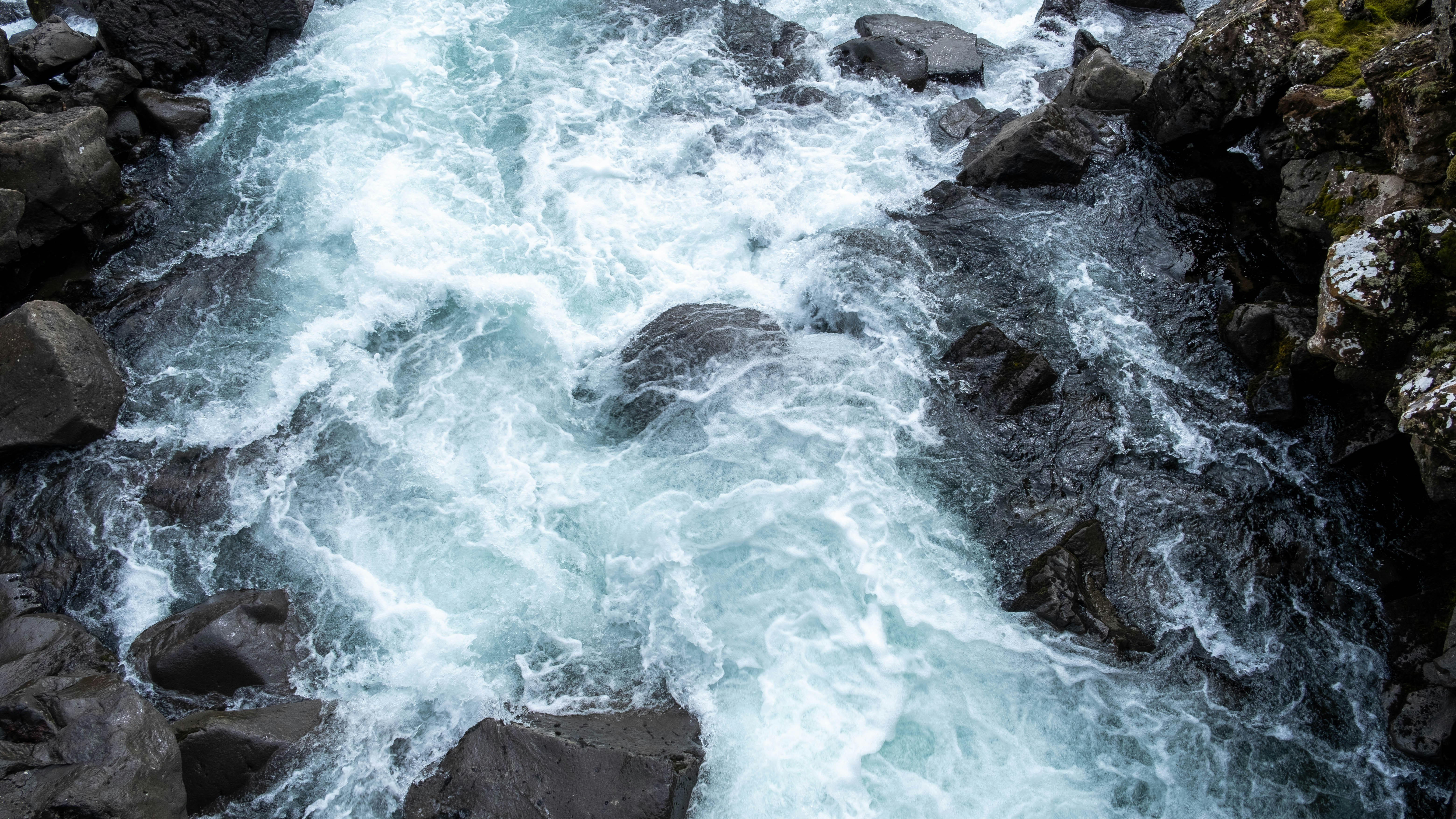 Rushing river water flowing over dark rocks, creating a dynamic interplay of movement and texture.