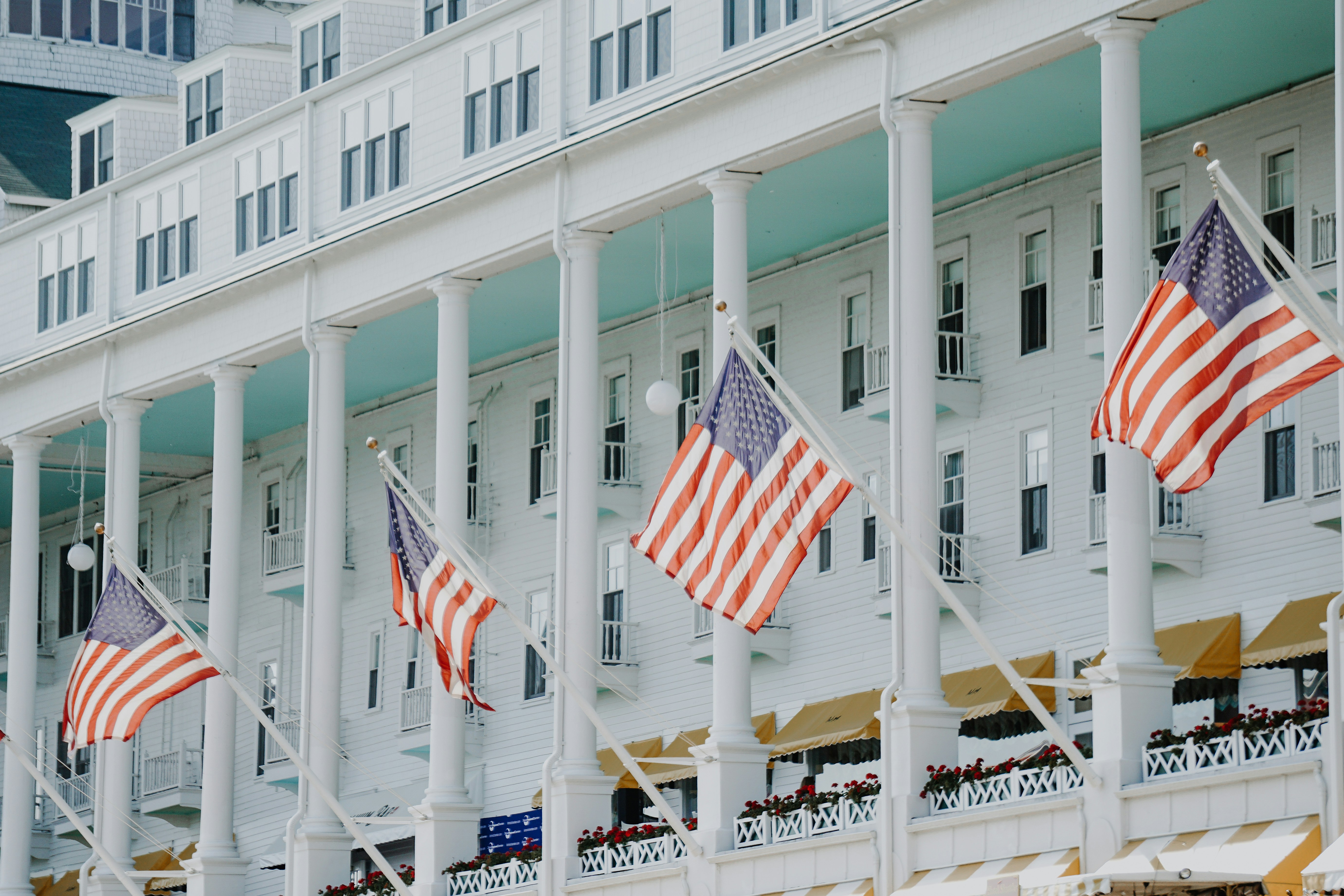 A row of american flags flying in front of a hotel photo – Free ...