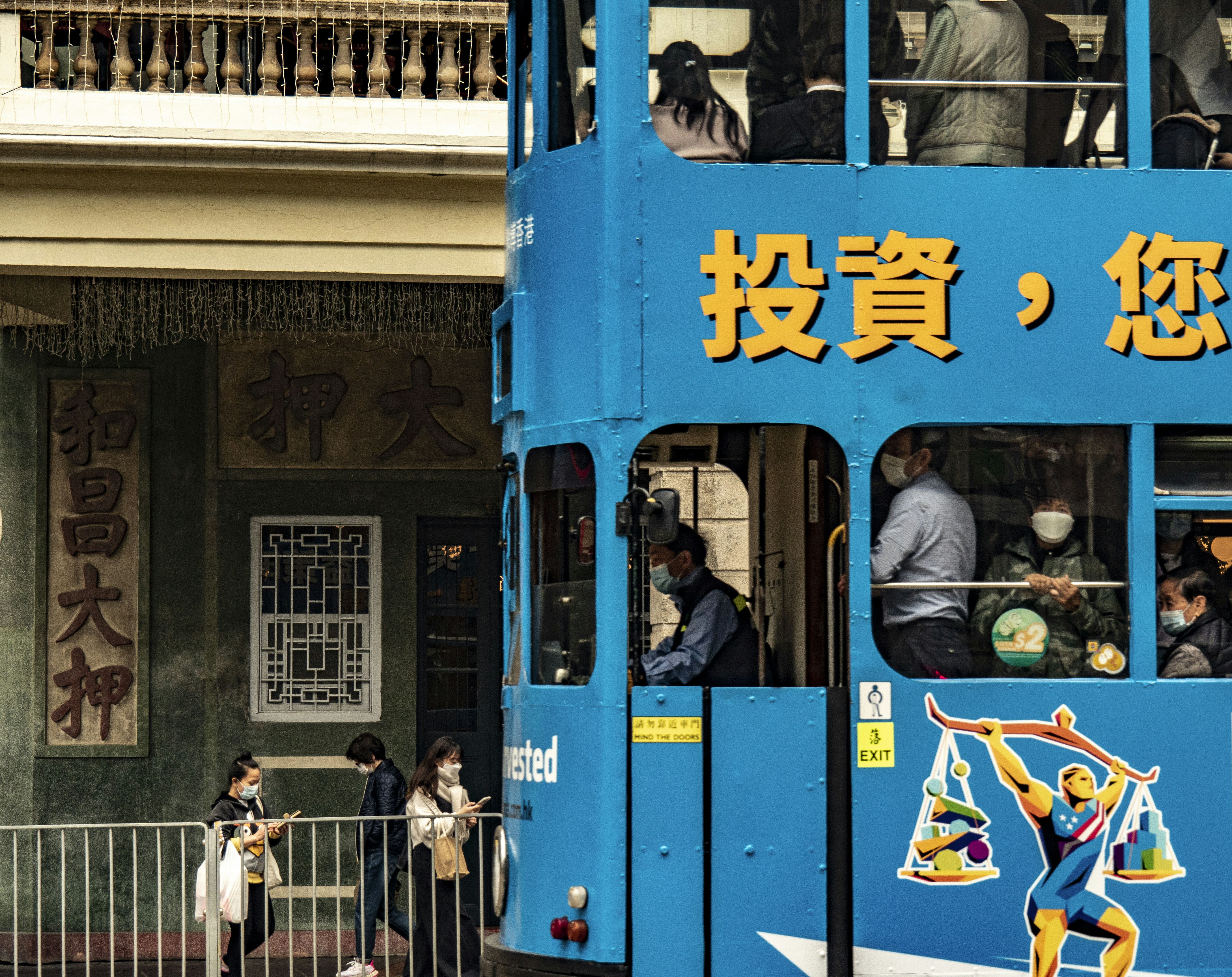 A blue double decker bus driving past a tall building photo – Free Hong ...