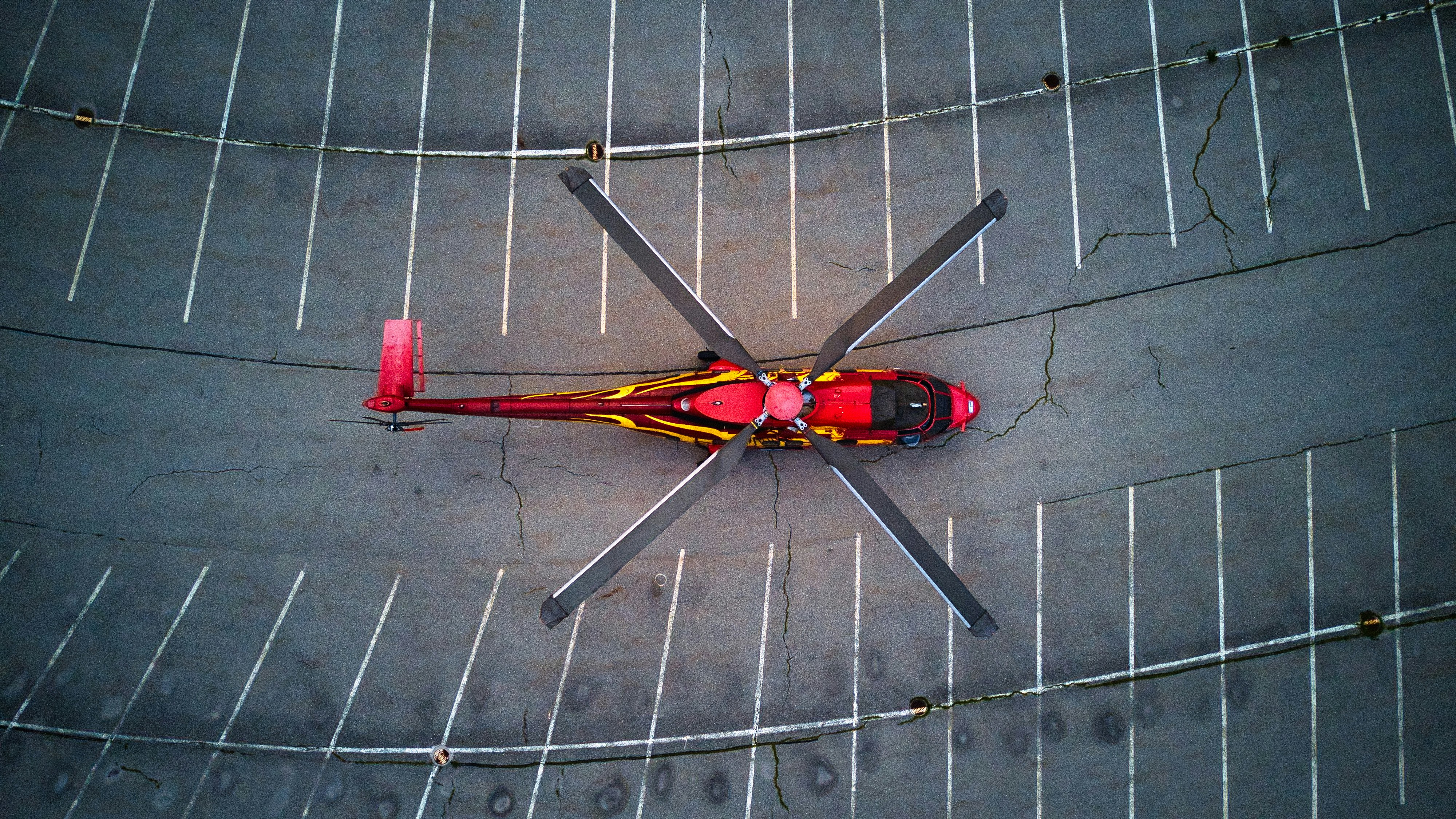 a red and yellow helicopter sitting on top of a parking lot