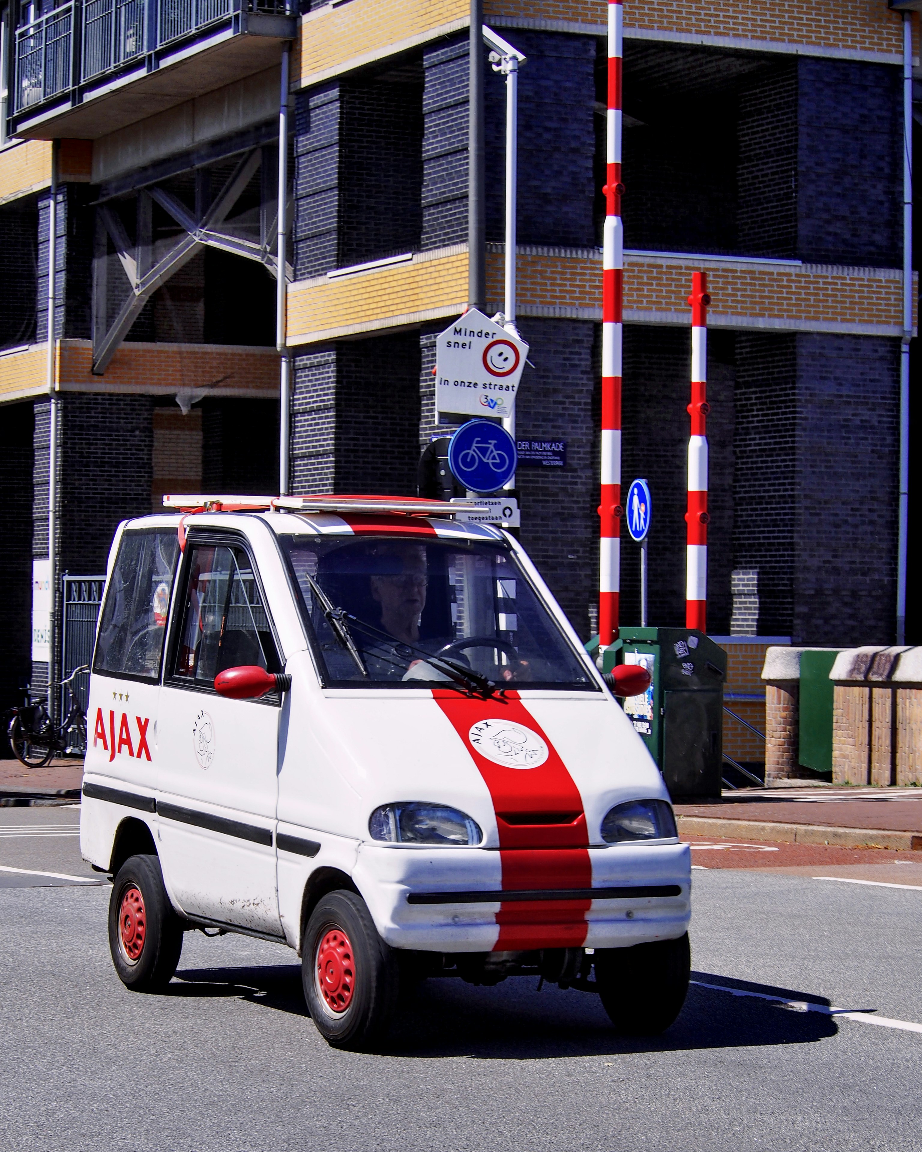 Red-stripe AJAX van under an urban construction canopy