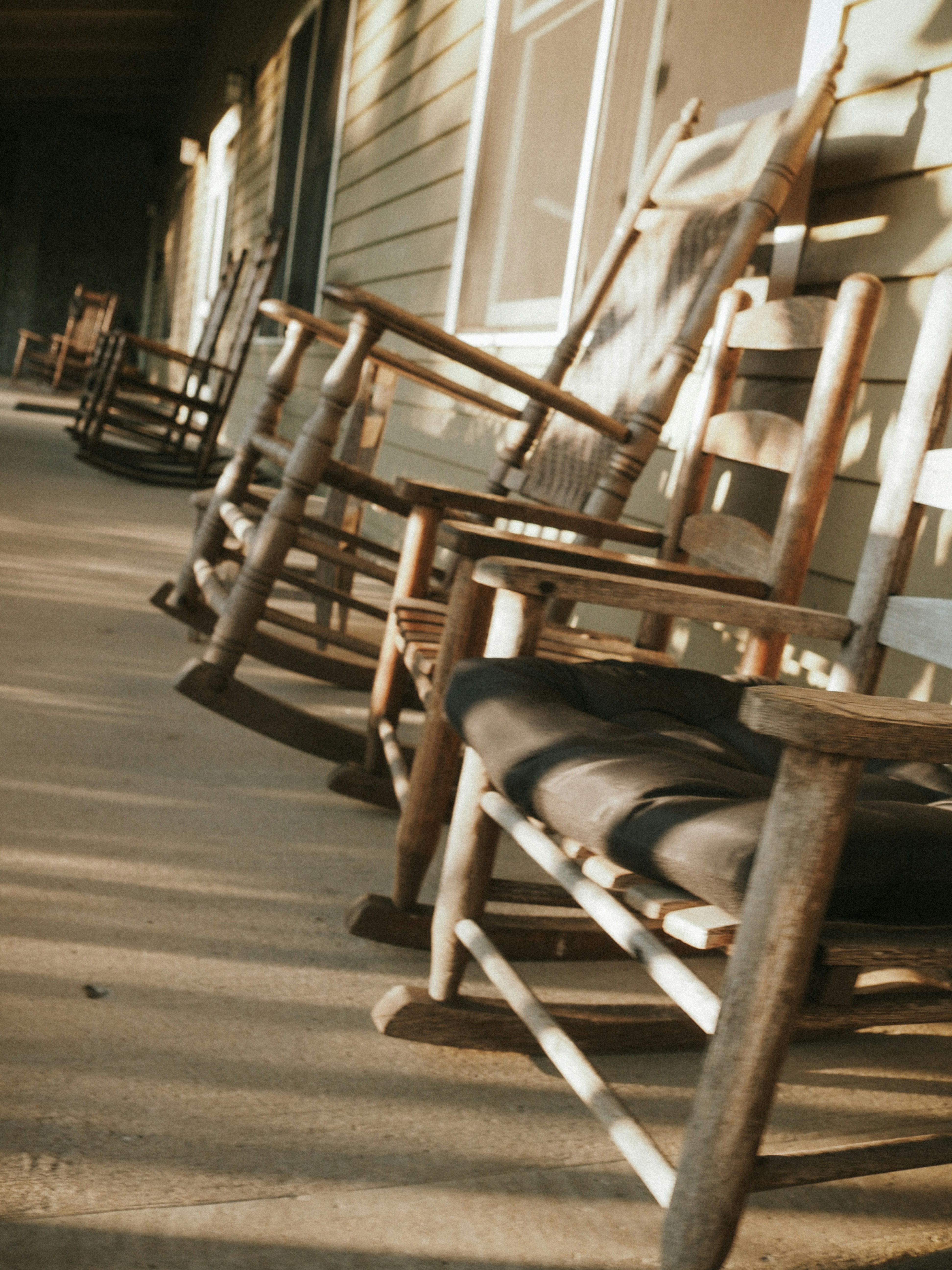 A row of wooden rocking chairs sitting on a porch photo – Free ...