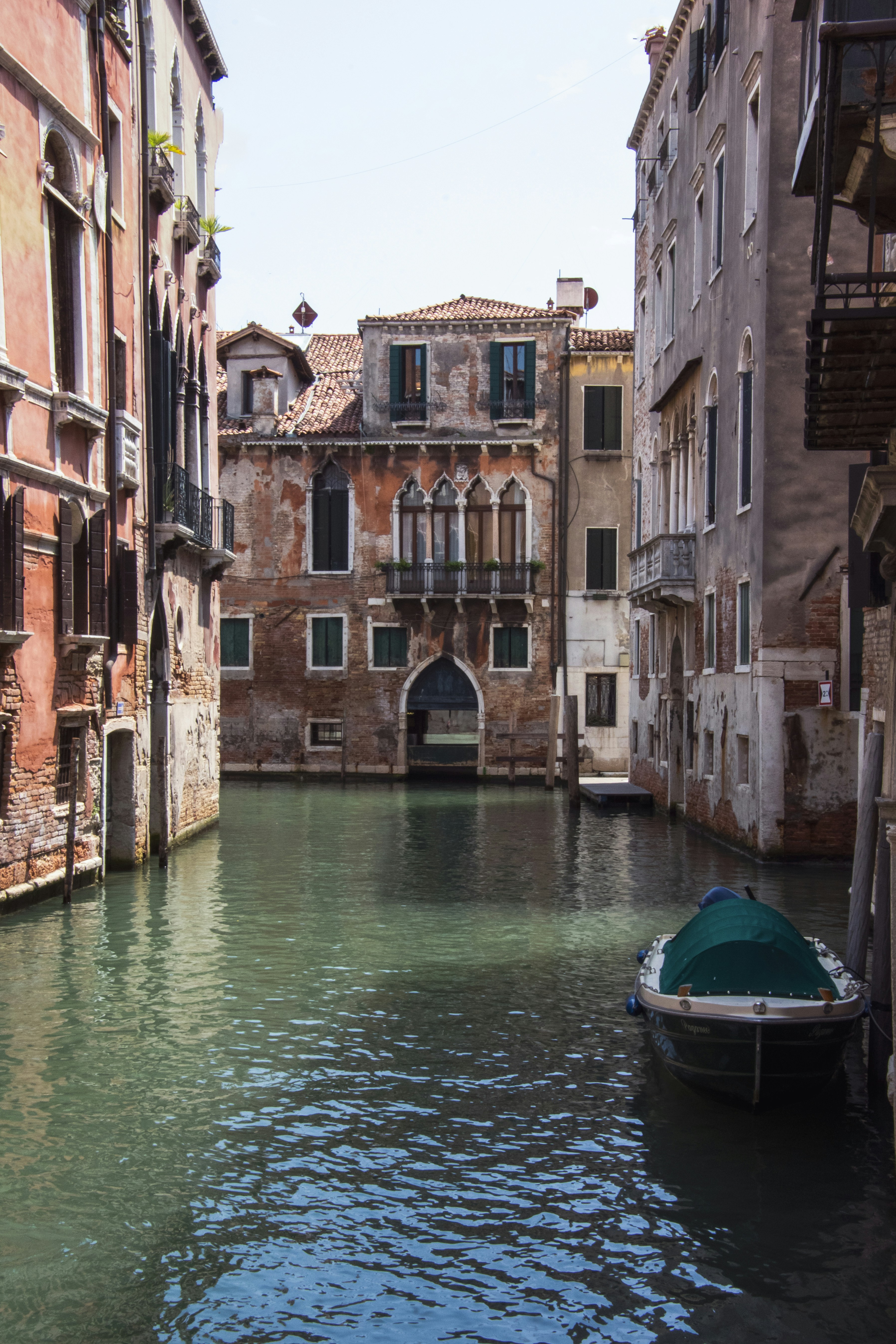 A boat floating down a river next to tall buildings photo – Free Canal ...