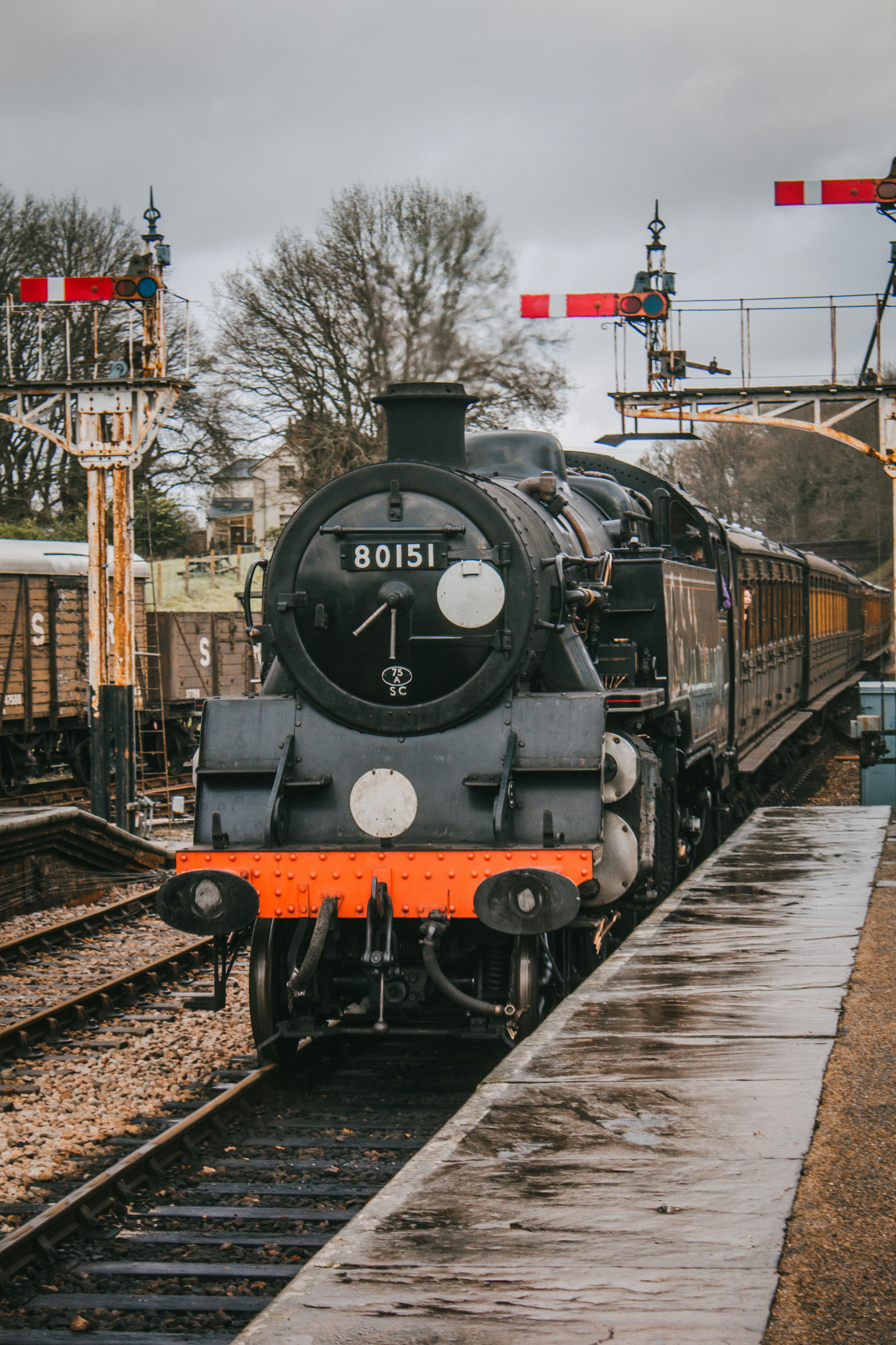 Iron Horse at the Crossing: Steam Engine Faces the Platform in Wet Light