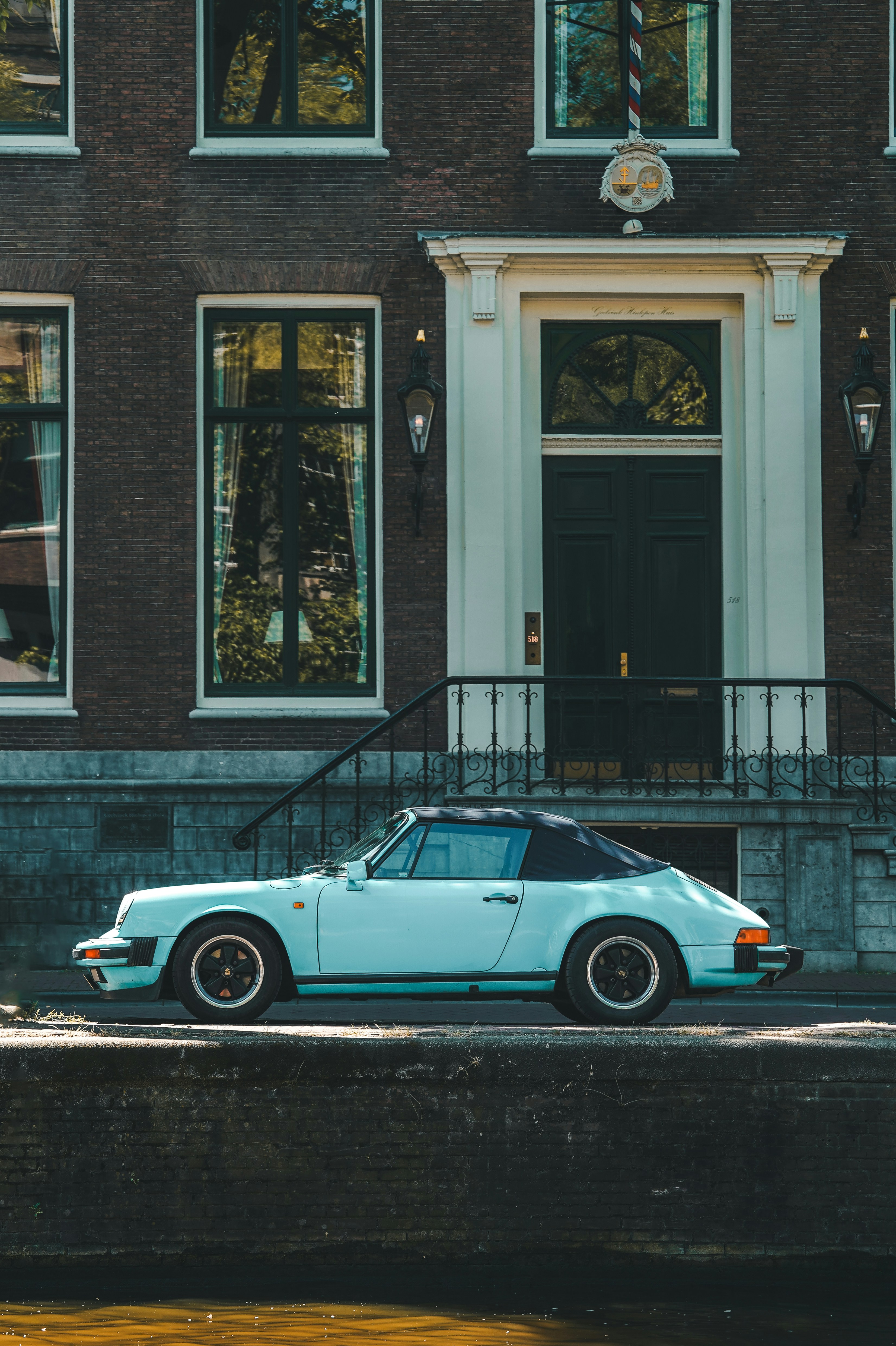 Azure Porsche 911 by a brick townhouse