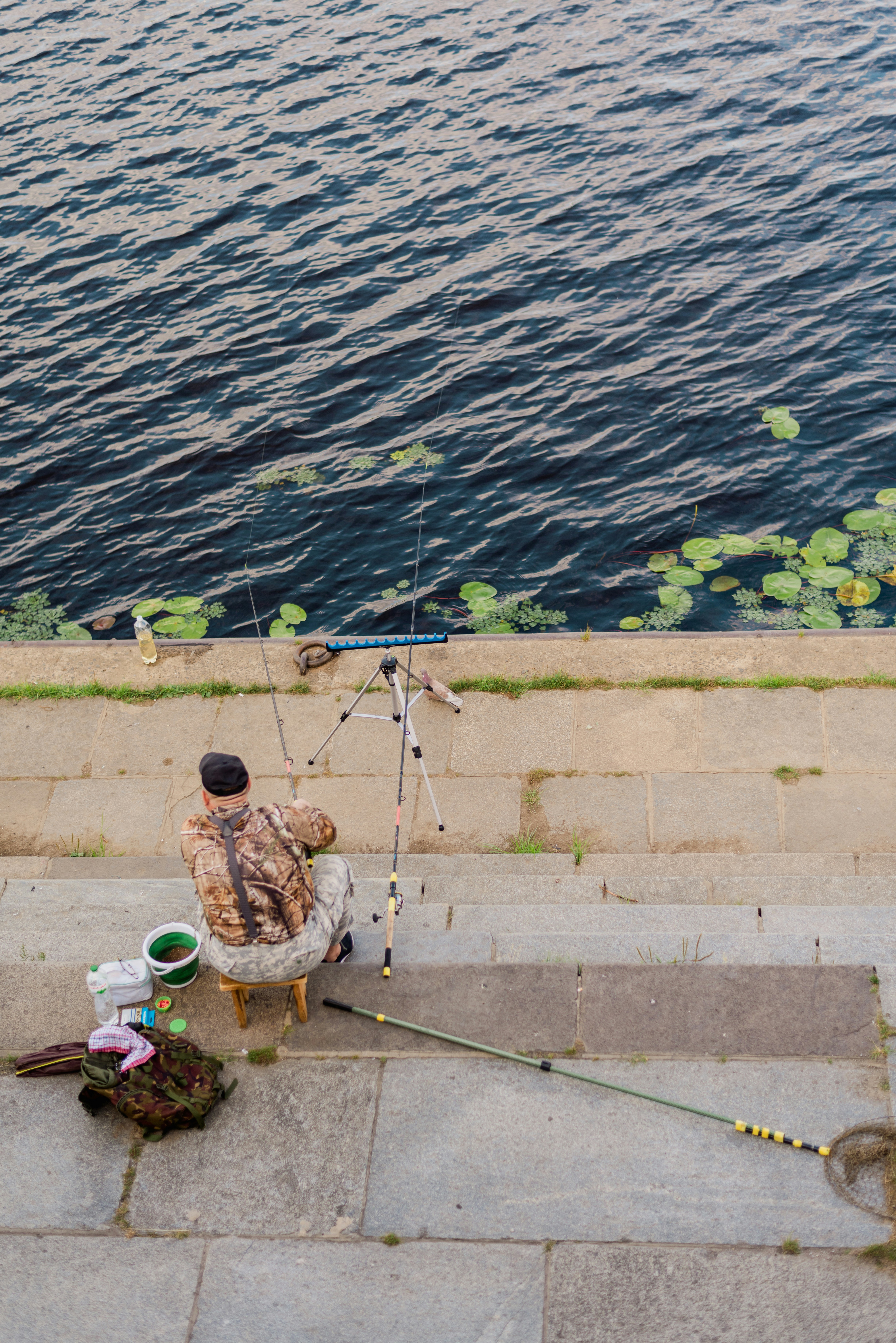 Riverside Stairs: Camouflaged Angler with Tripod and Rods