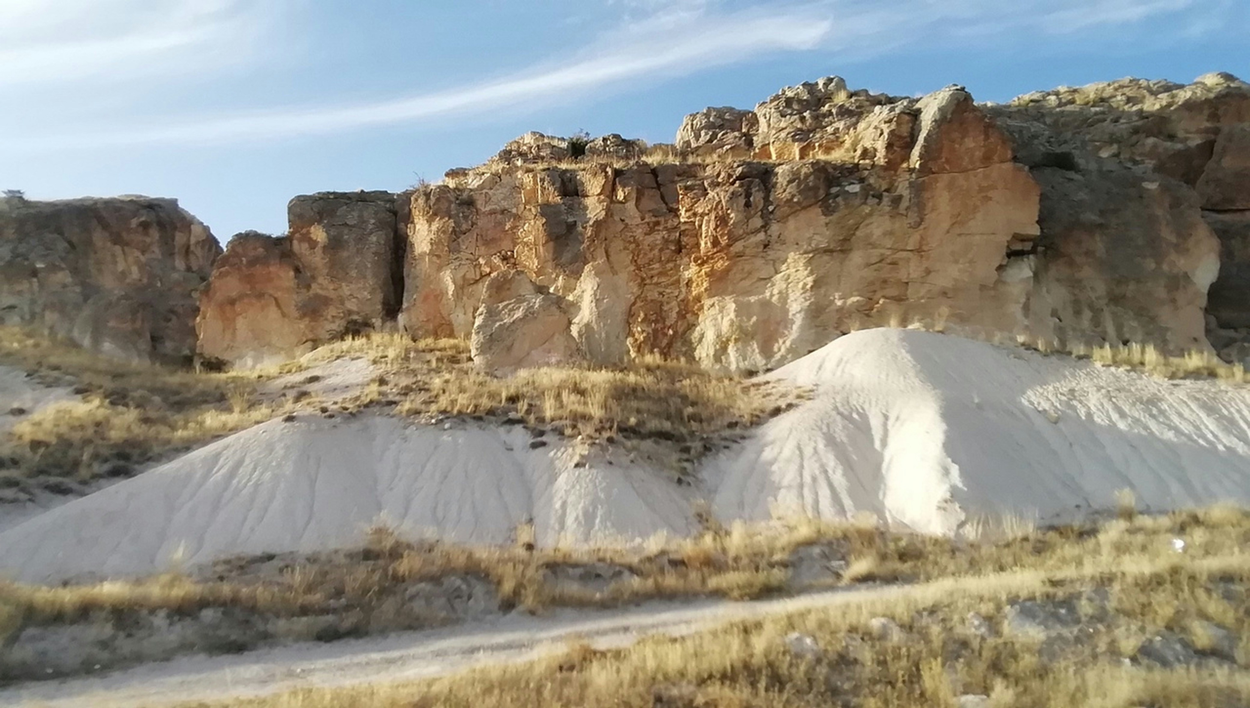 A group of large rocks sitting on top of a dry grass field photo – Free ...