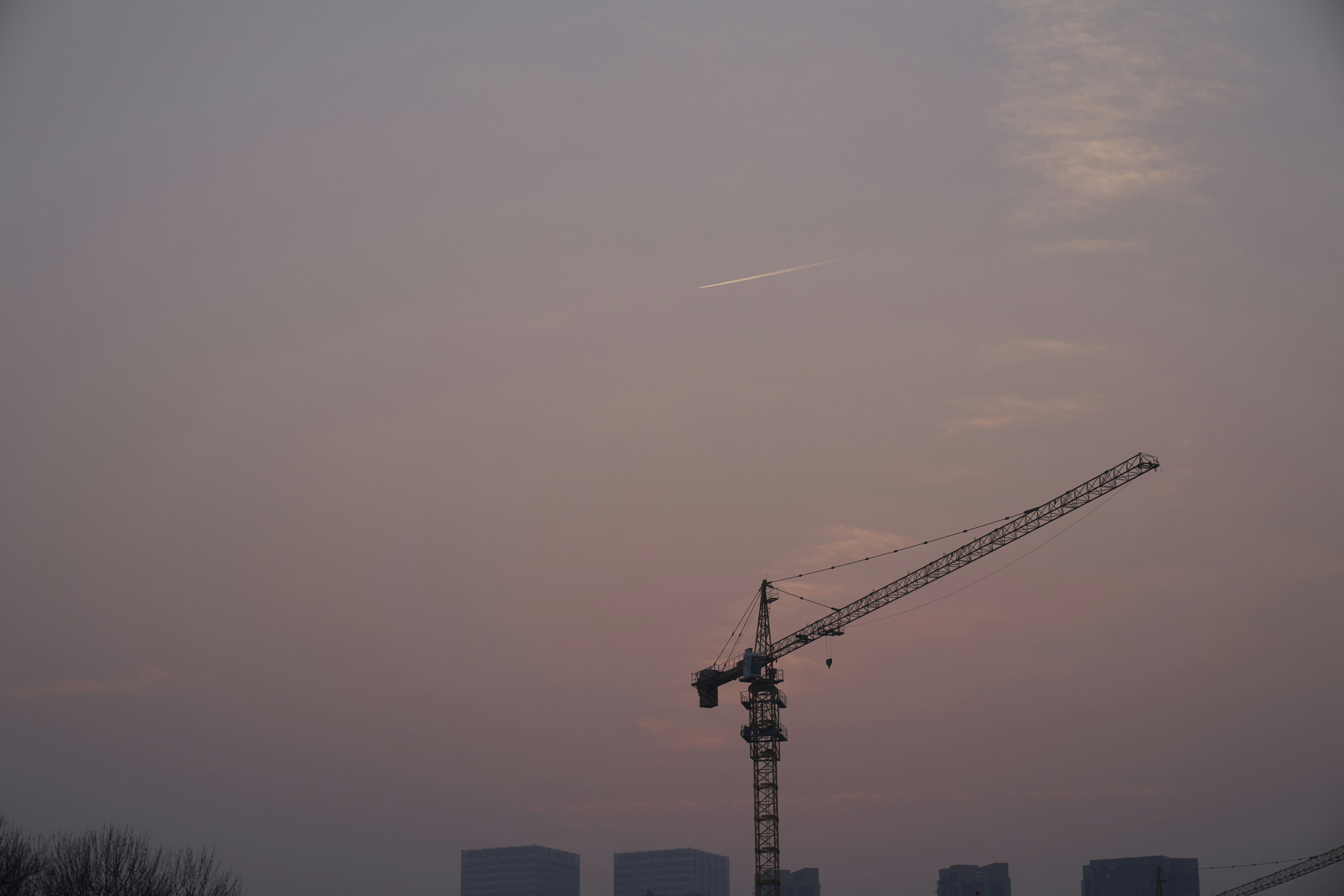 Crane Silhouette Against a Lavender Sunset Over a Quiet City Horizon