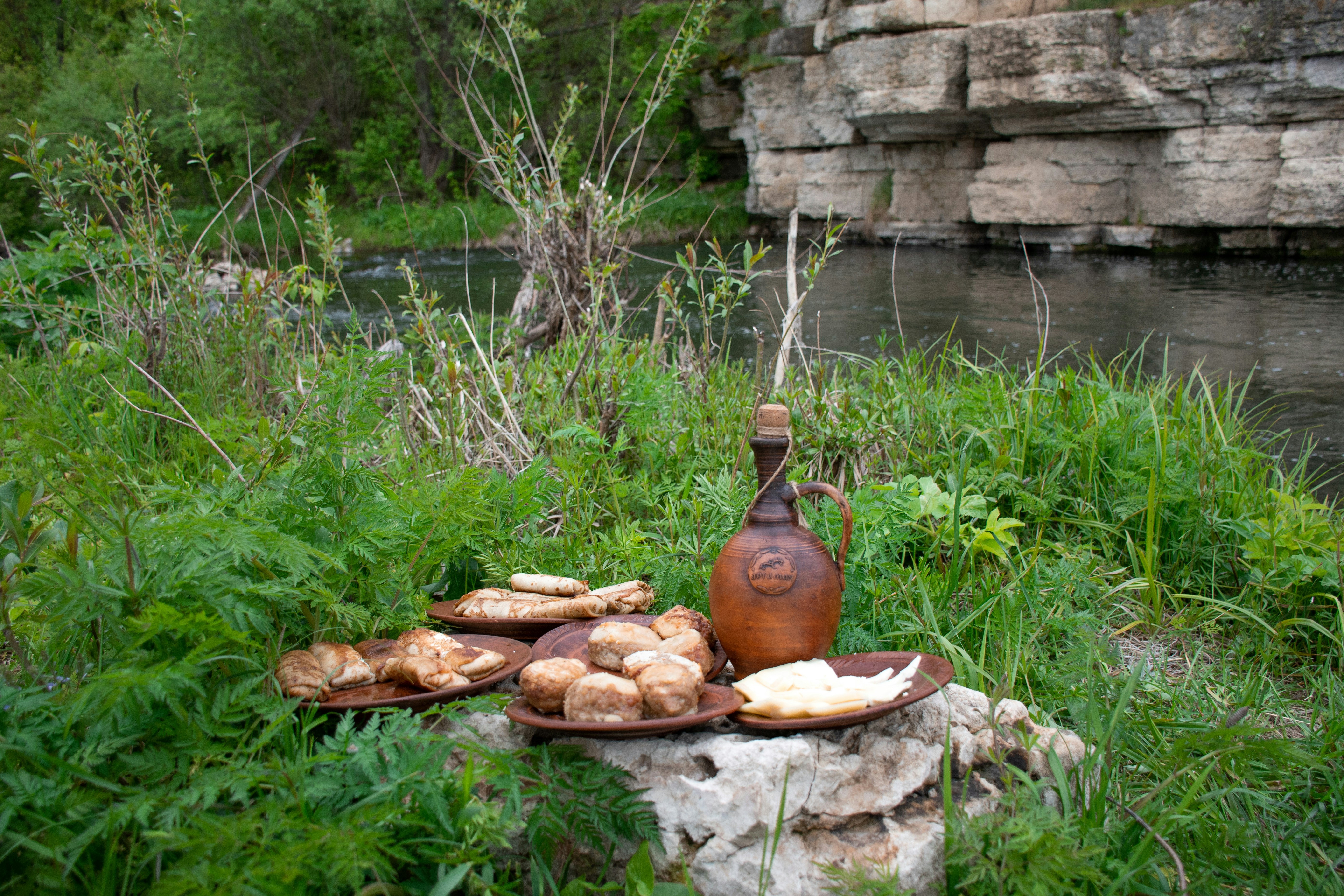A plate of food sitting on top of a rock next to a river photo – Free ...